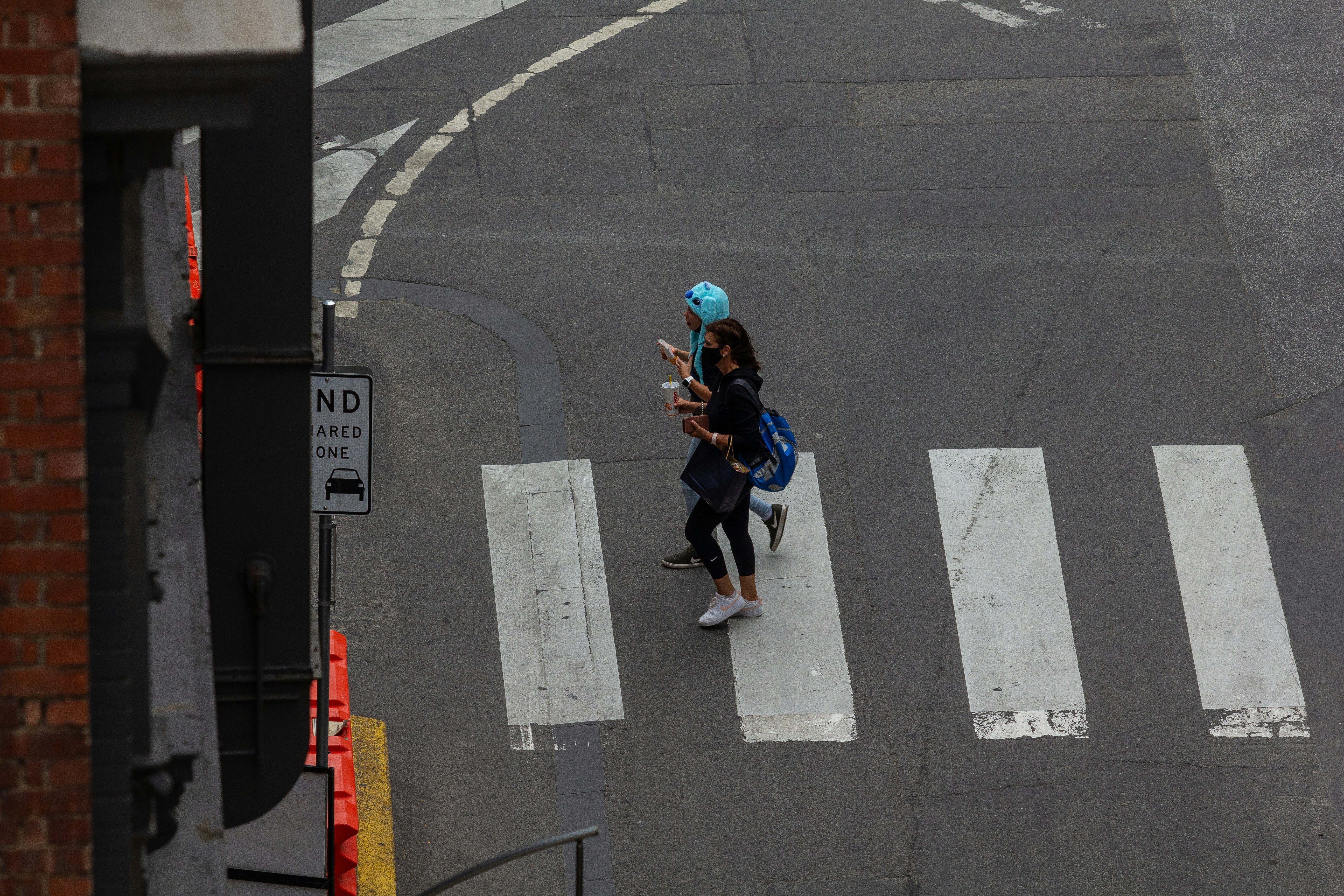 Overhead Crossing: Two Pedestrians Navigate a Painted Crosswalk Beneath City Shadows