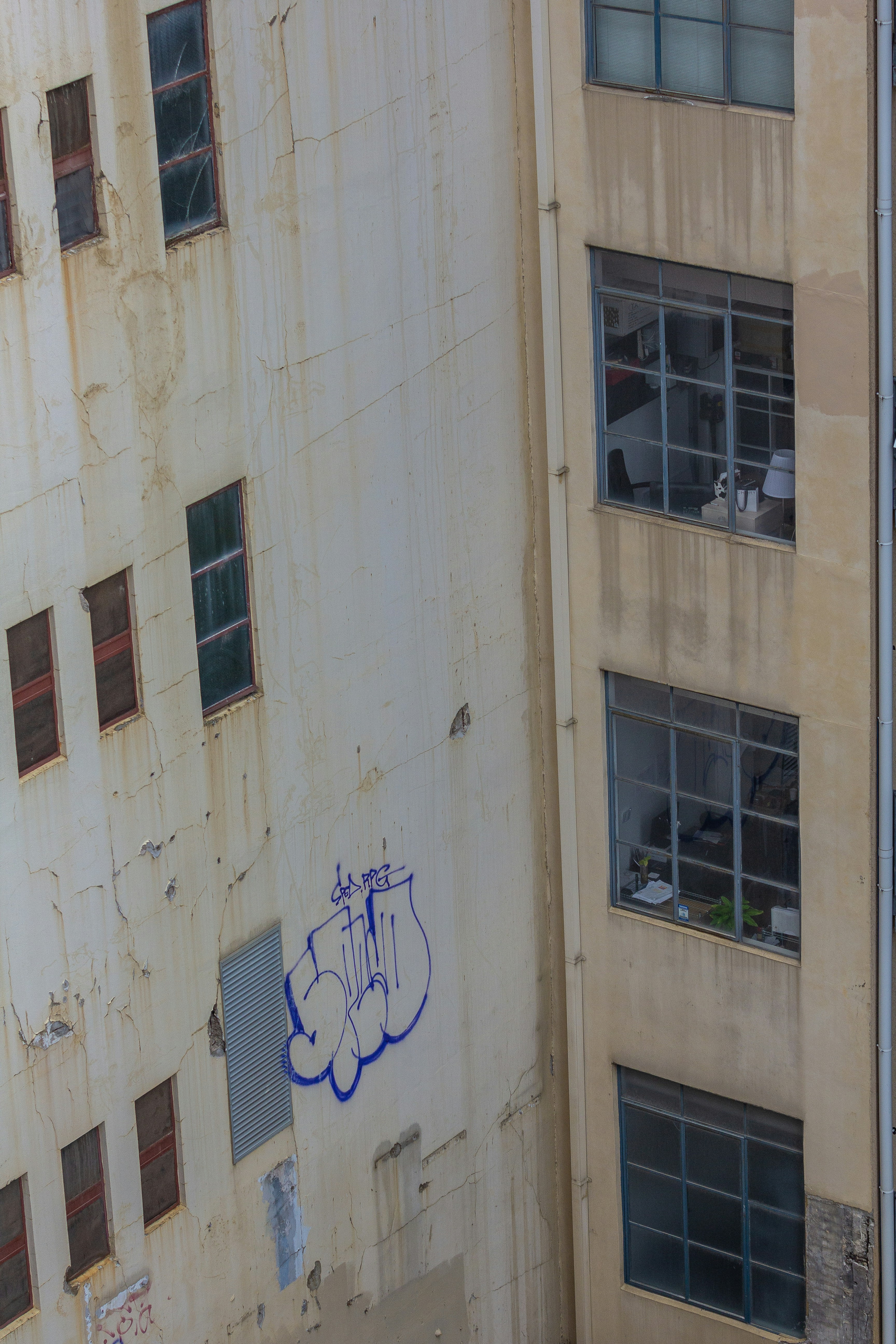 Blue Graffiti on a Weathered Facade Framing a Windowed City Pulse