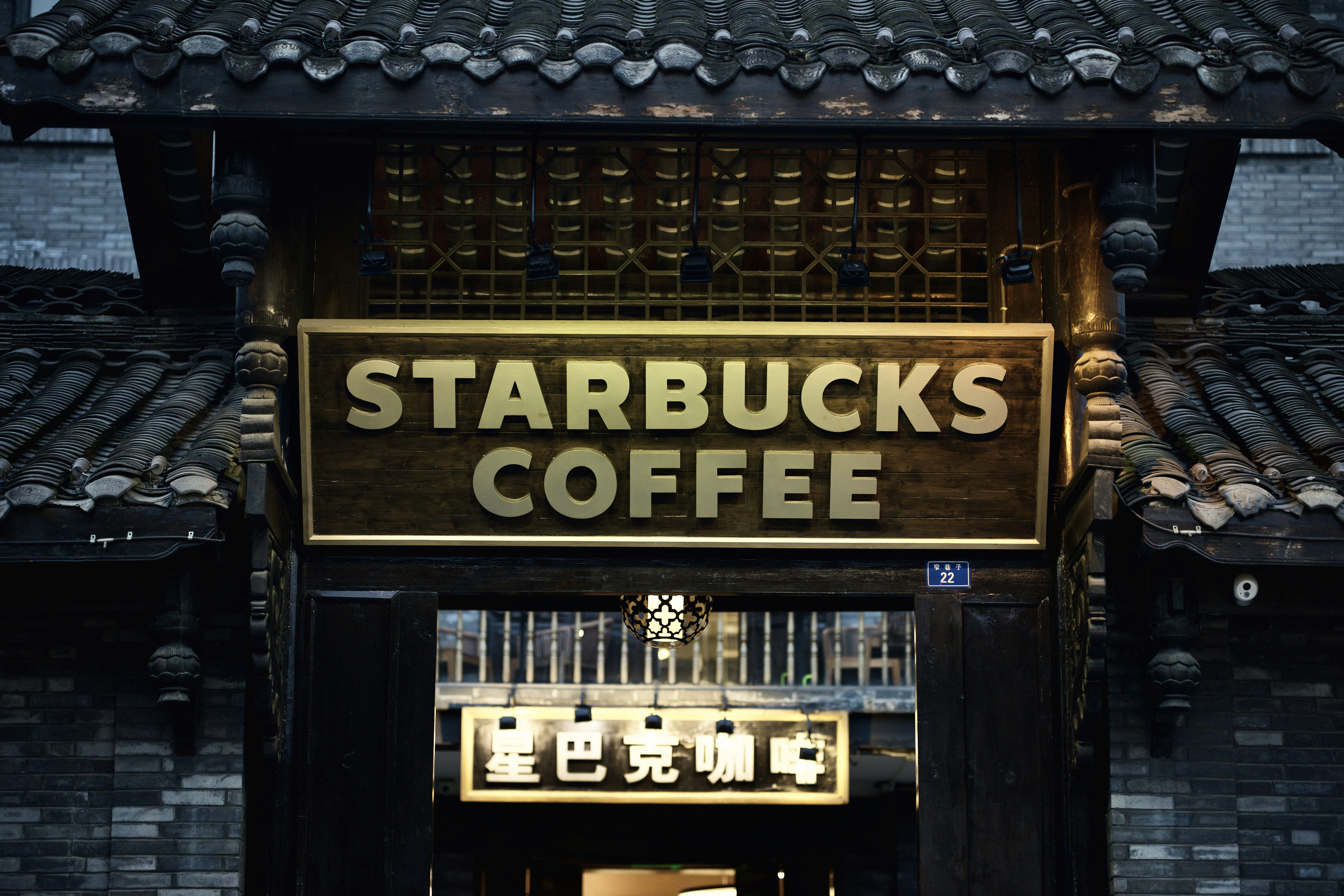 Illuminated Starbucks Coffee sign at a traditional architectural entrance, showcasing a blend of contemporary branding and classic design elements.