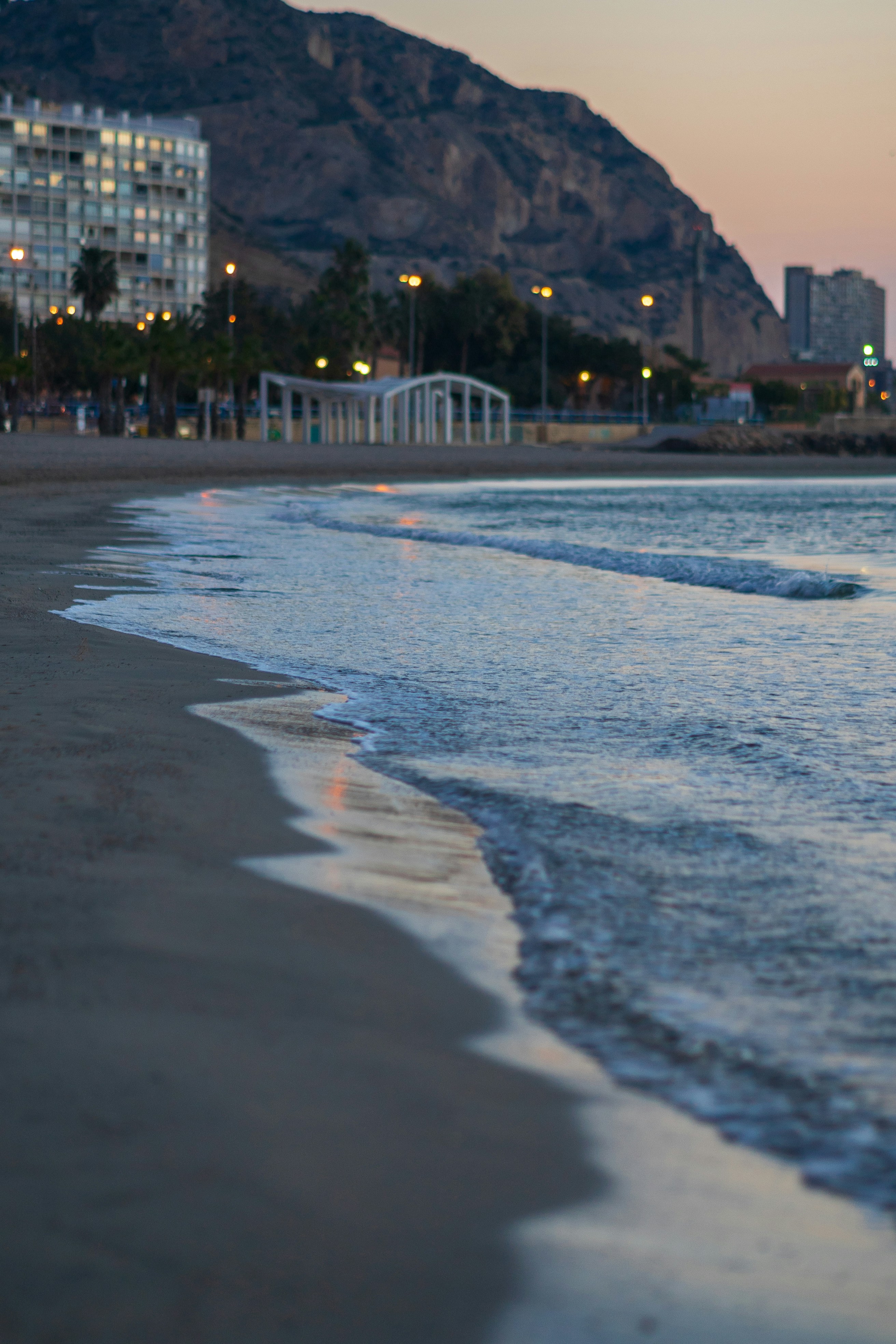 Twilight Shoreline: A Quiet Urban Beach with a Distant White Bridge