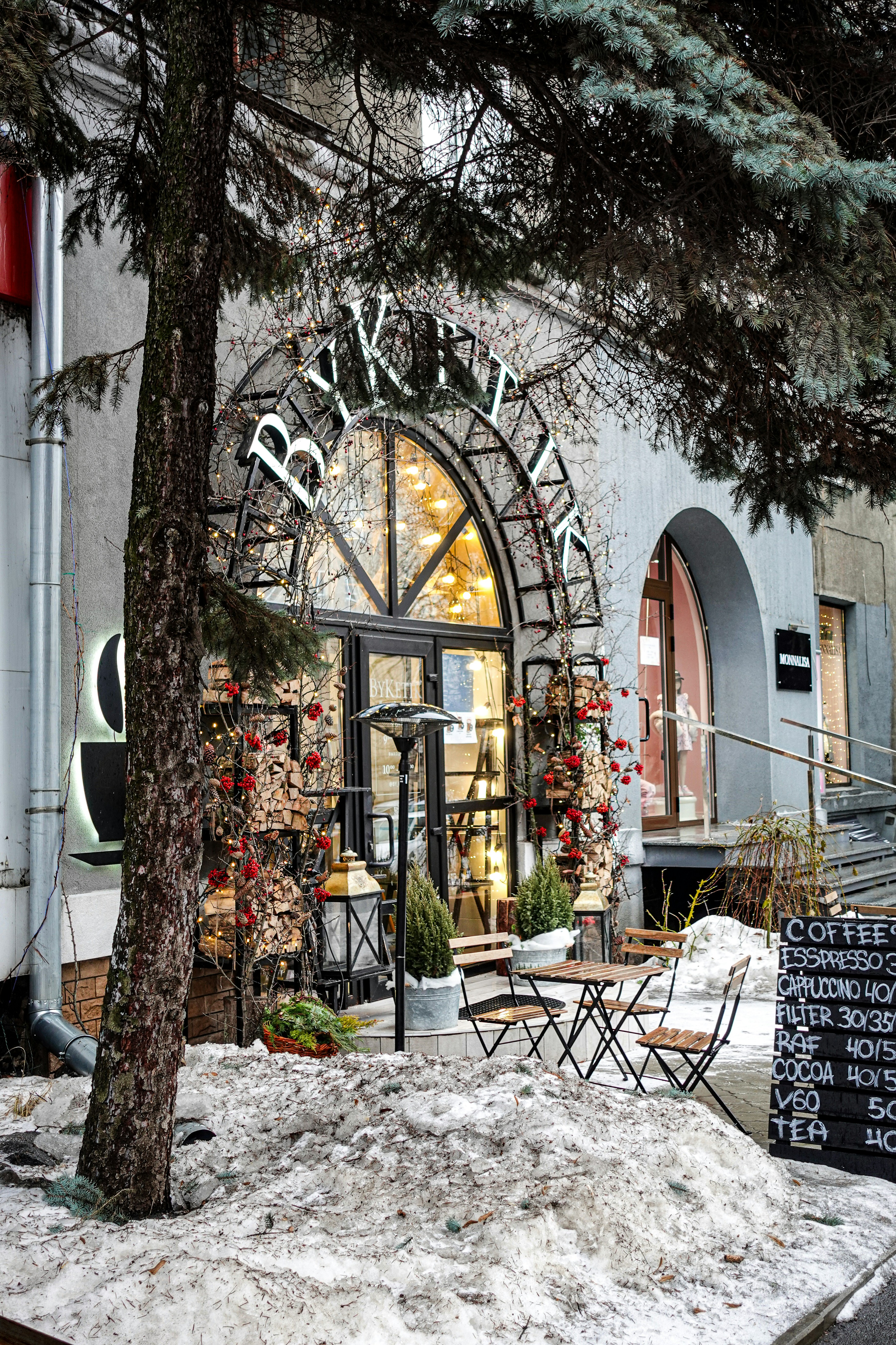 Snow-Dusted Café Beneath a Wrought-Iron Arch Bathed in Warm Glow