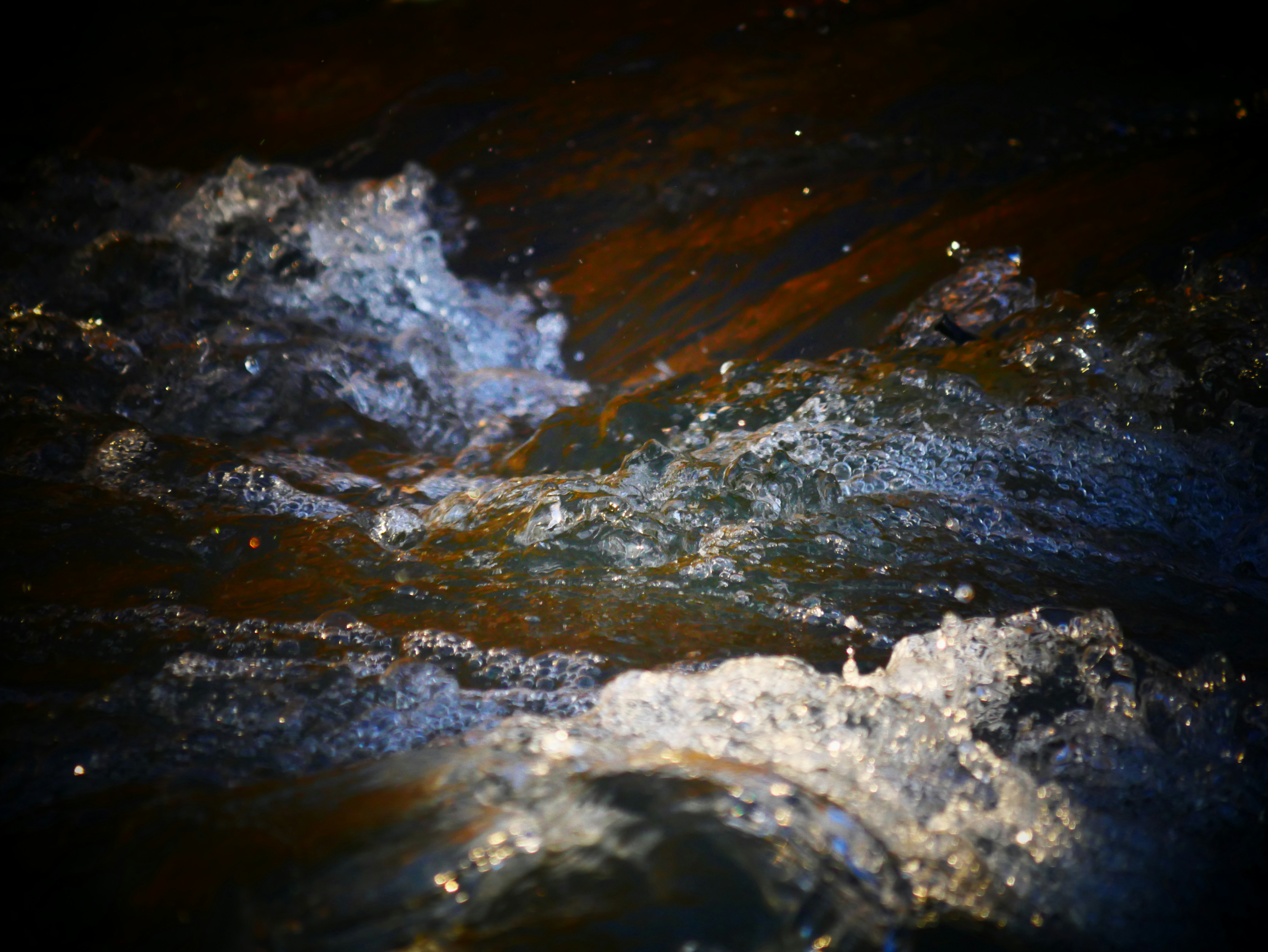 Close-up of swirling water capturing the dynamic movement and texture of flowing streams in natural light.
