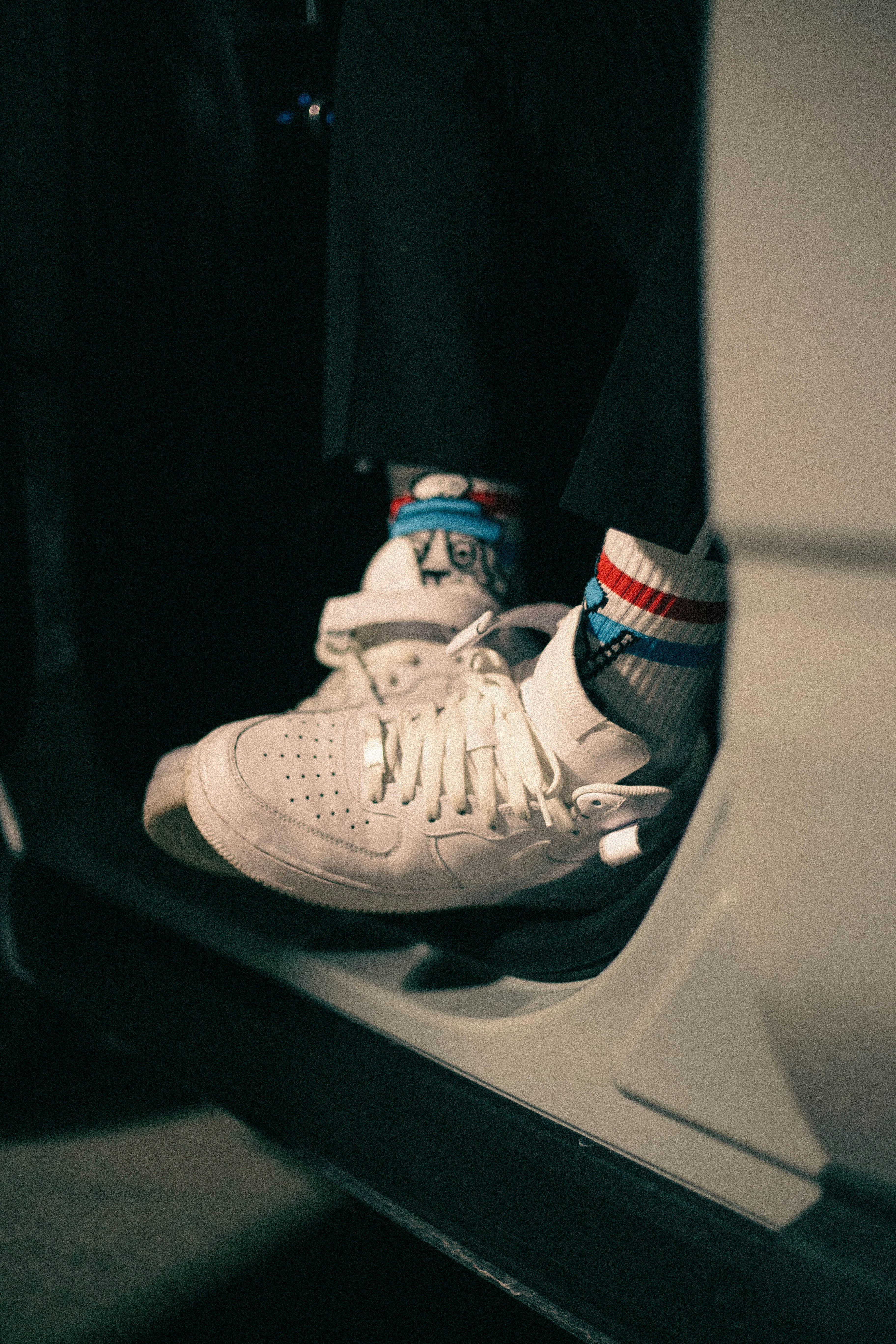 White sneakers paired with colorful socks peek out from the open door of a vehicle, showcasing a blend of casual fashion and urban lifestyle.