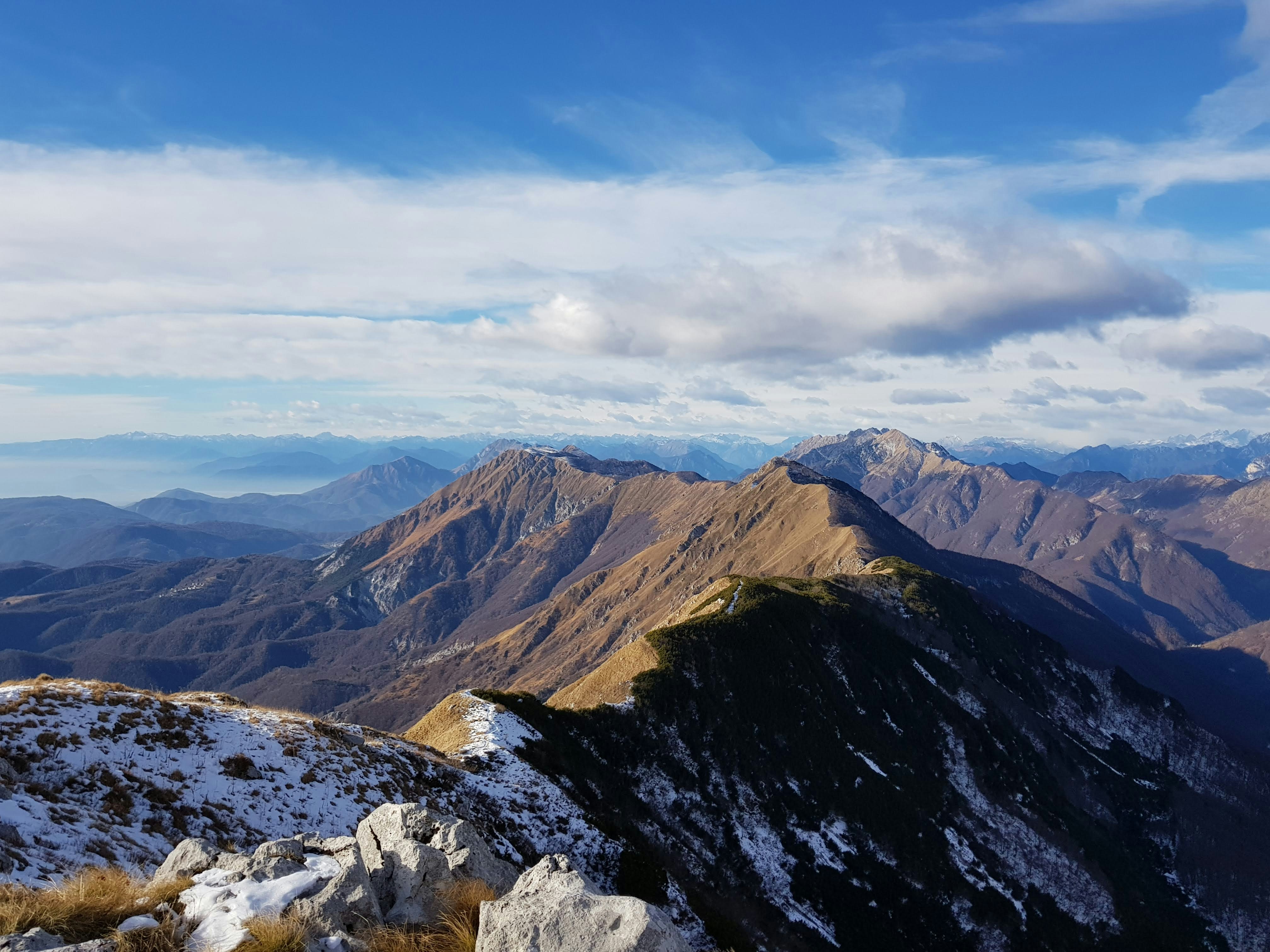 Majestic mountain range under a clear sky, showcasing the interplay of rocky peaks and lush valleys. Snow-capped summits contrast with the earthy tones of the slopes.