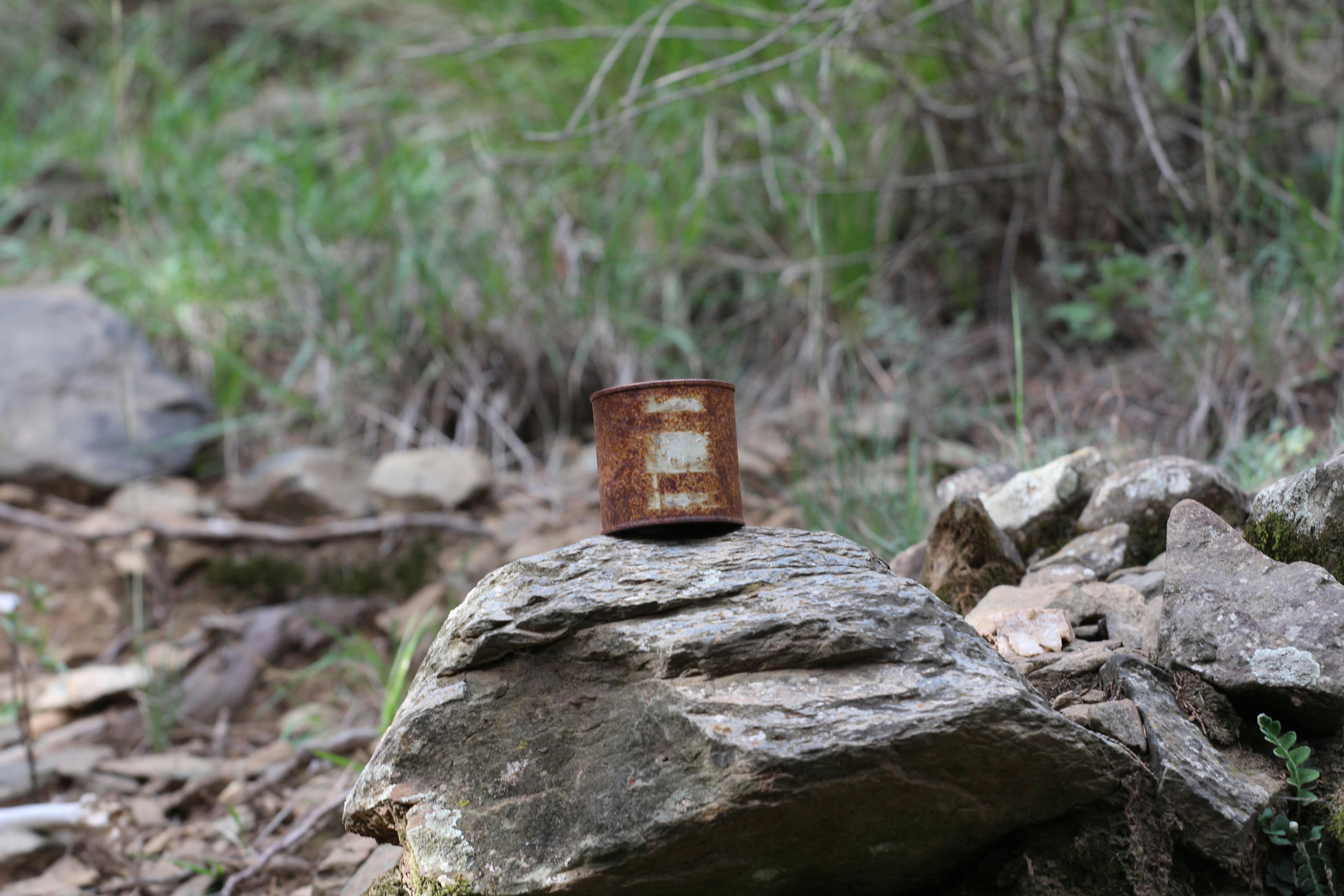 a rusty cup sitting on top of a rock