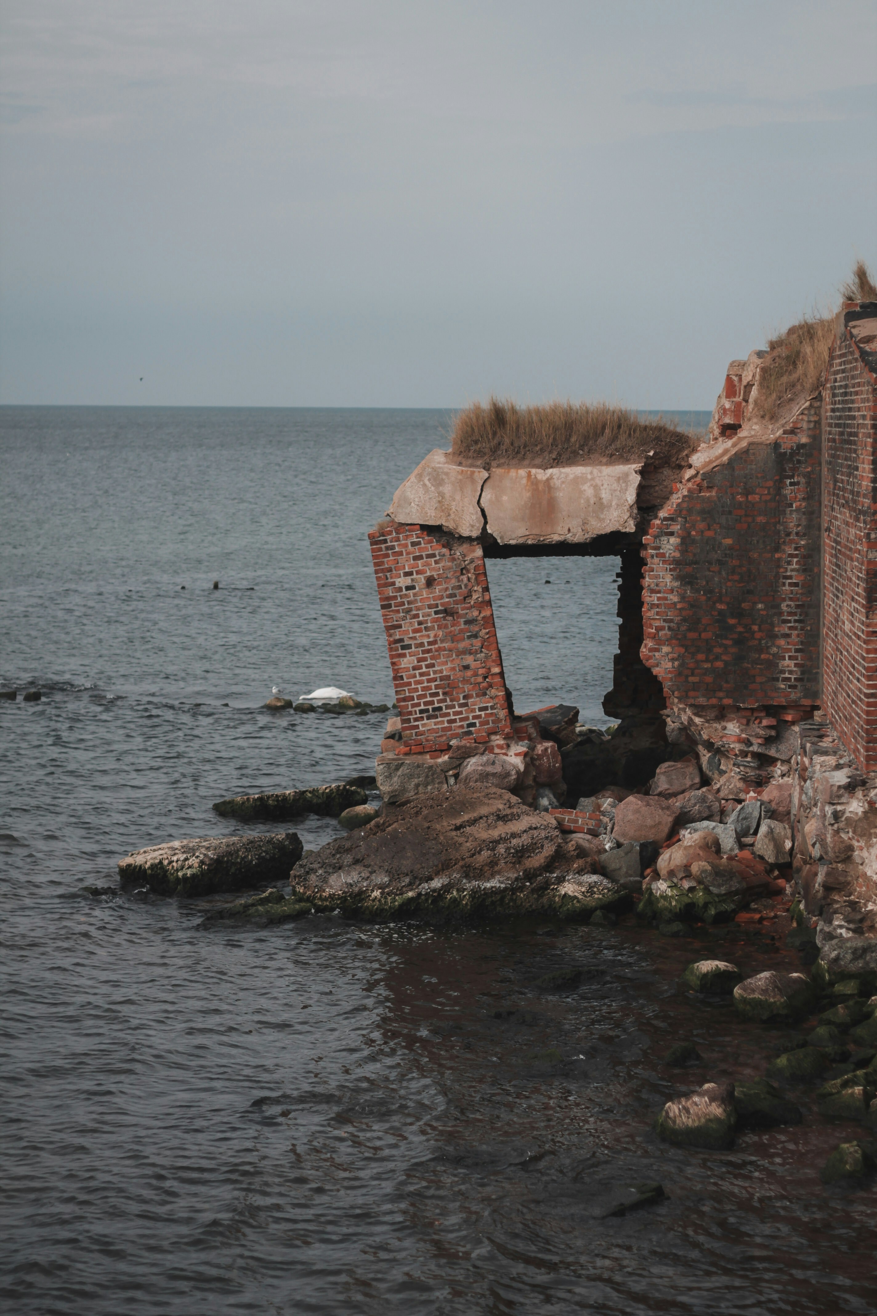 an old brick building sitting on top of a rocky shore
