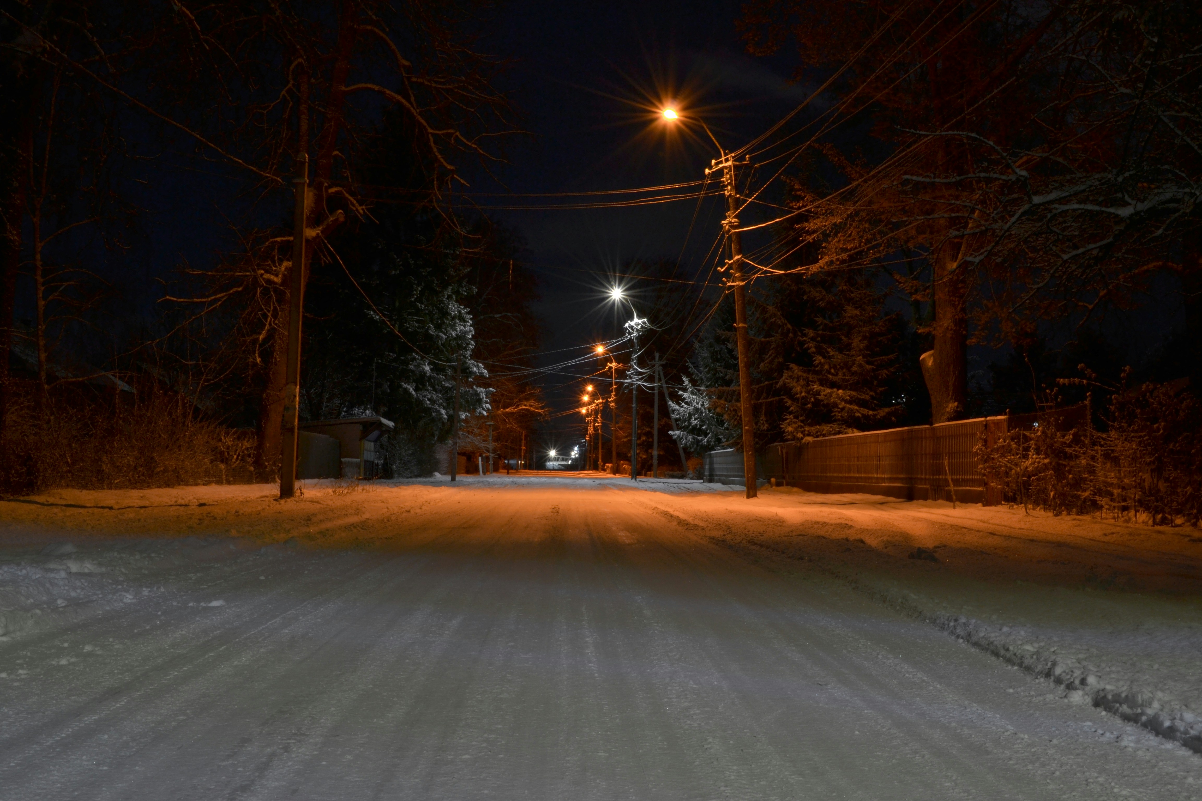 Snow-covered street illuminated by streetlights, creating a serene winter atmosphere at night.