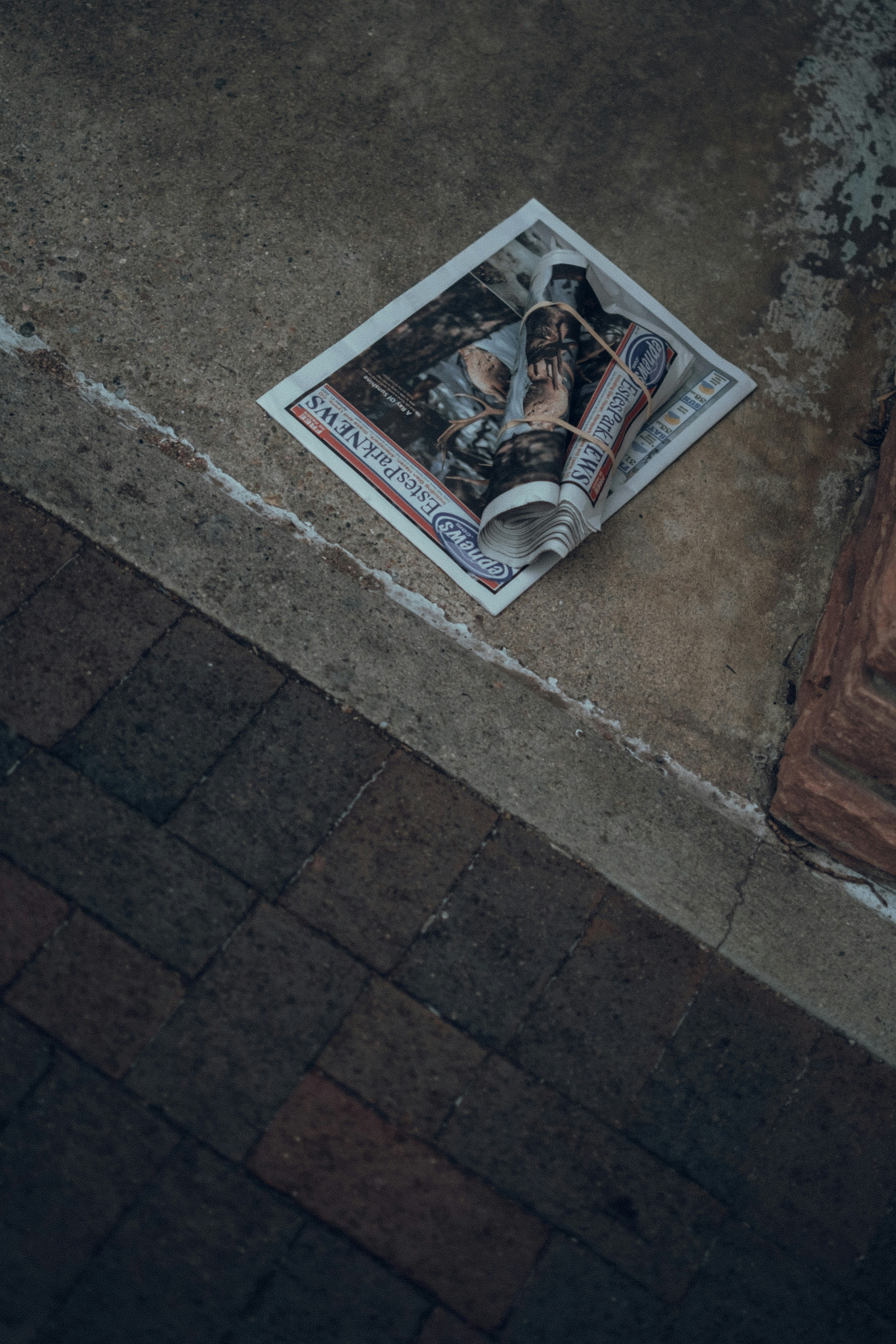 A newspaper laying on the ground next to a door photo – Free Grey Image ...