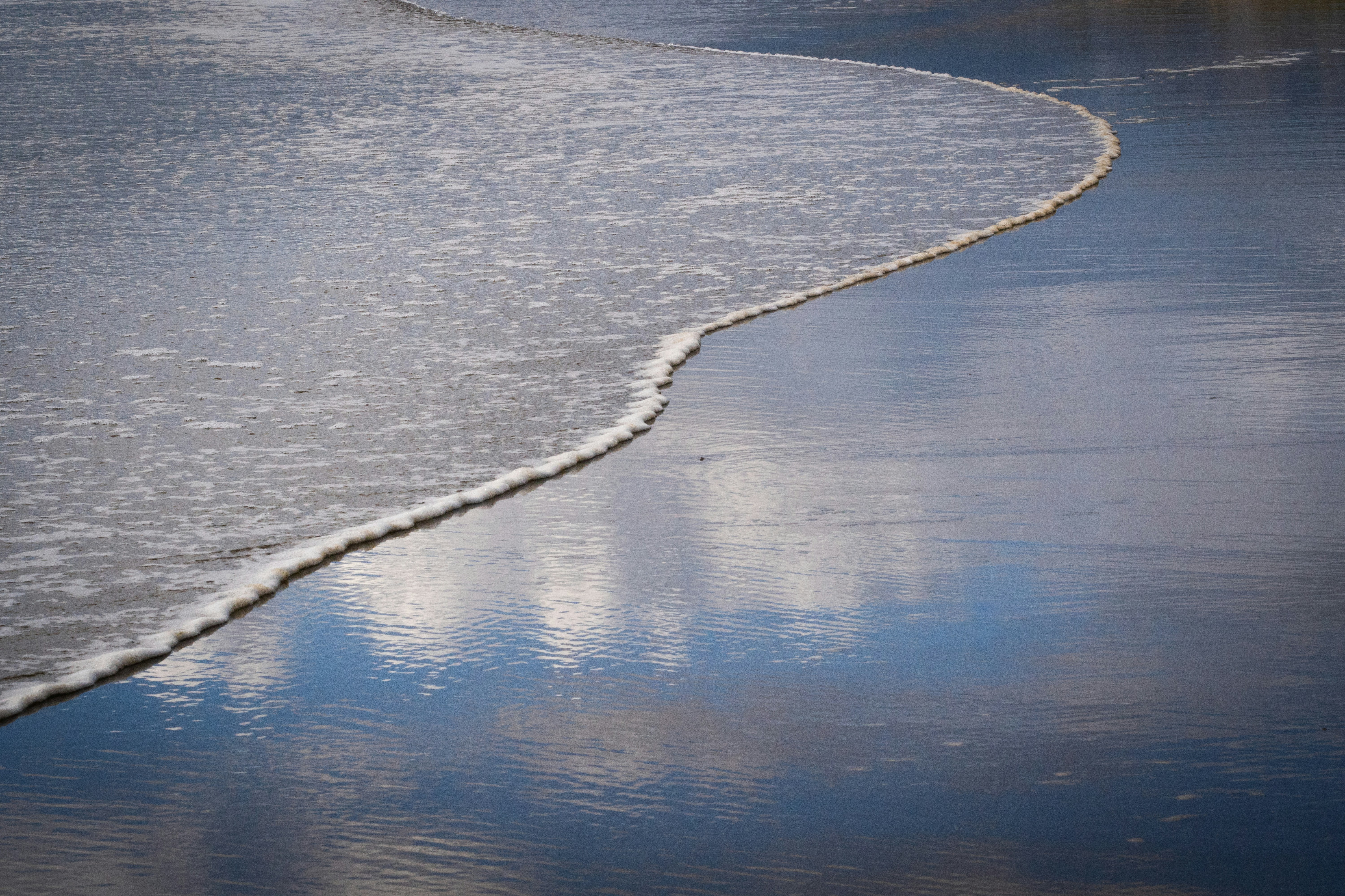 A wave is coming in to the shore of a beach photo – Free Grey Image on ...
