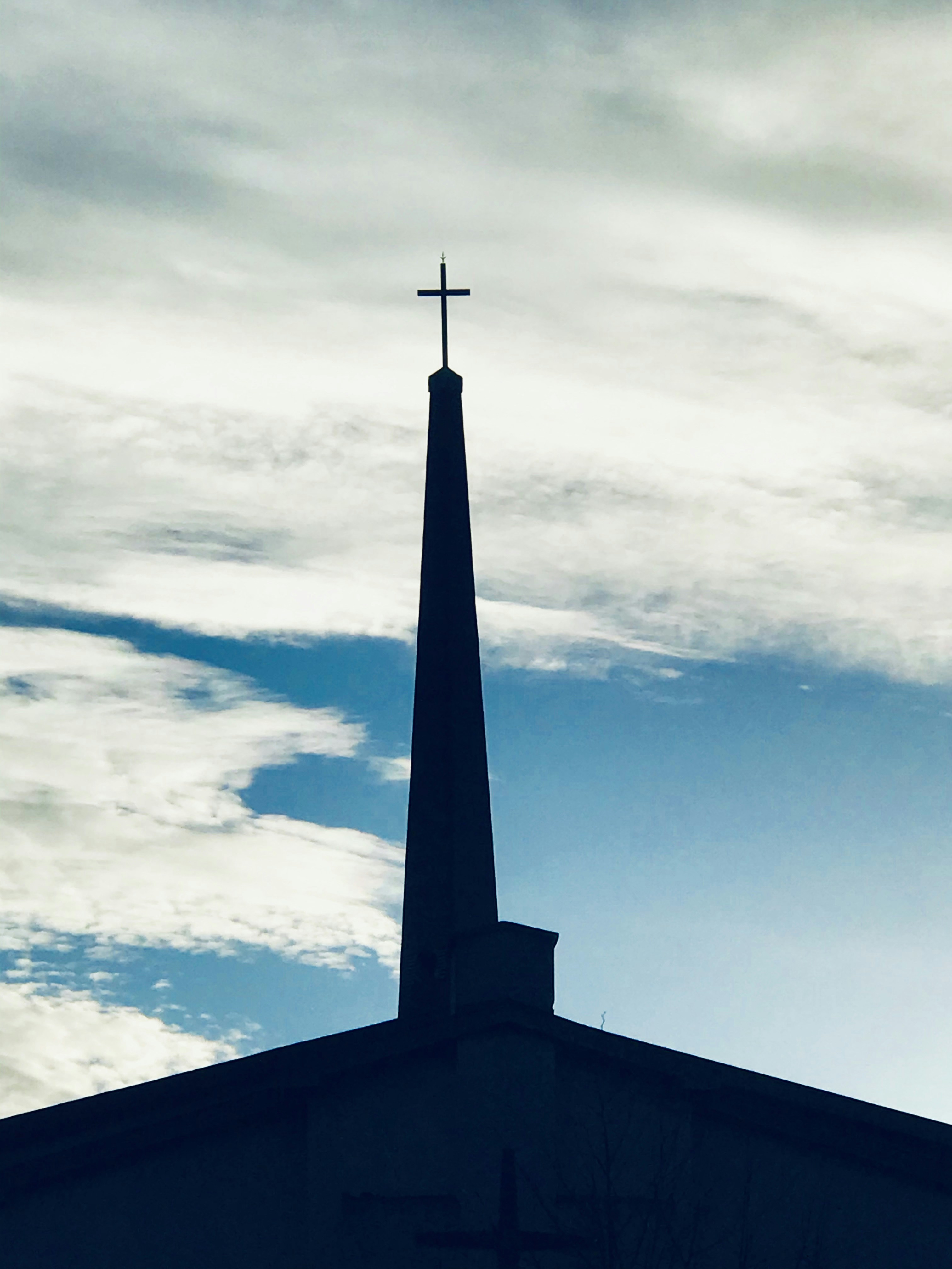 'Cross with clouds' : Church with a Christian cross at the top against a clouded sky. | a church steeple with a cross on top
