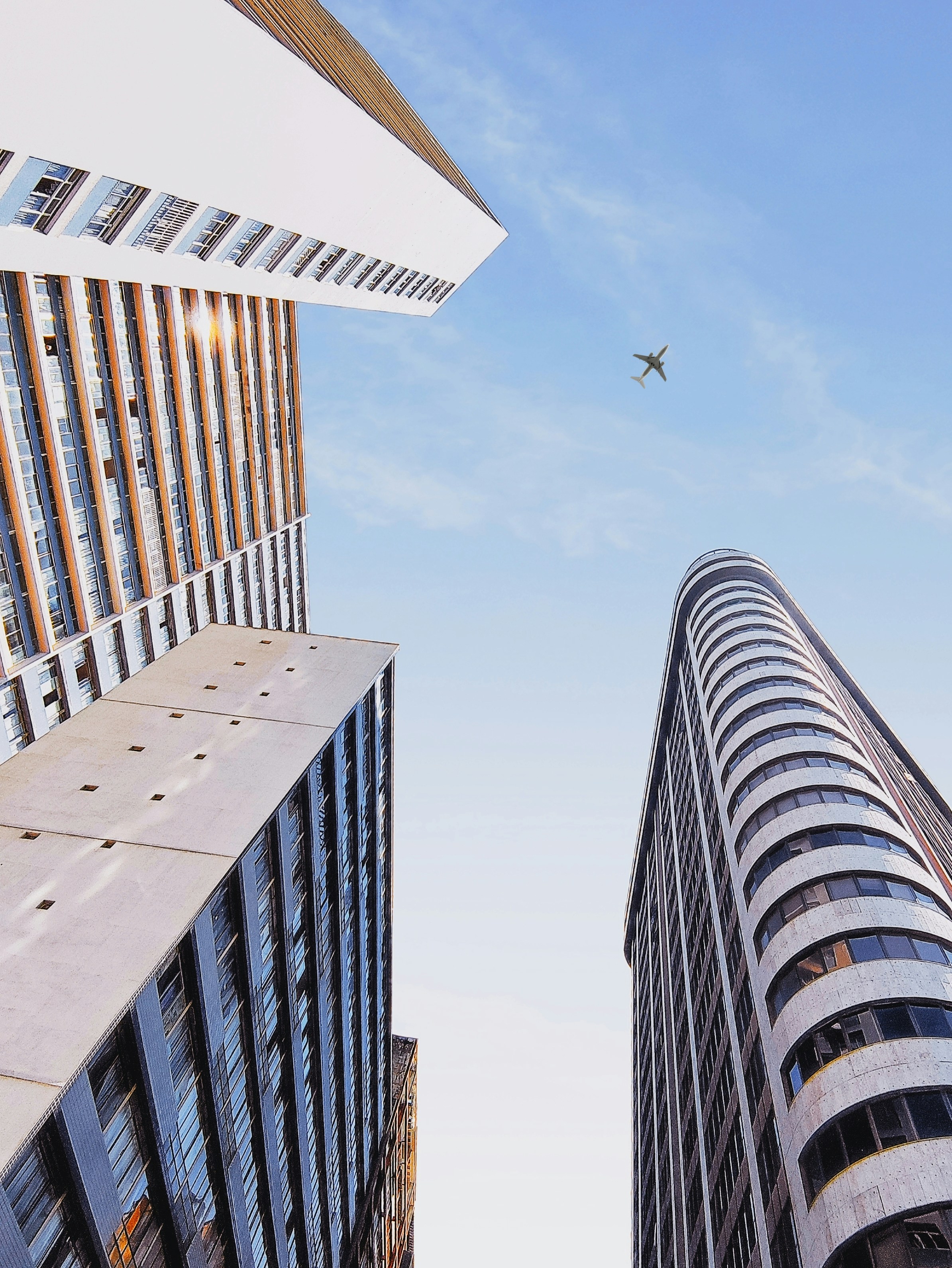 A plane flying over a tall building in a city photo – Free Building ...