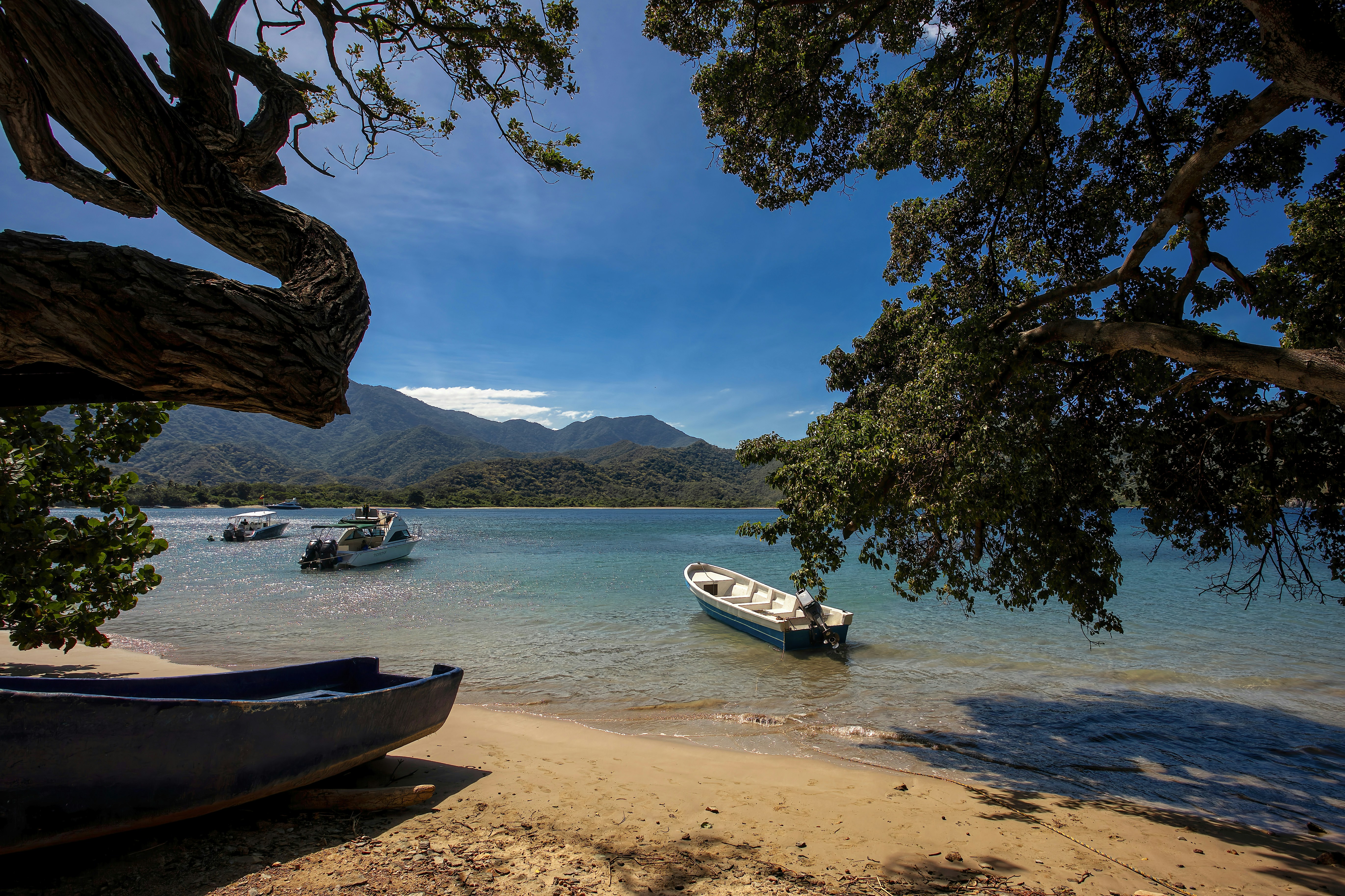 Sunlit Cove: Boats, Sand and Silent Mountains
