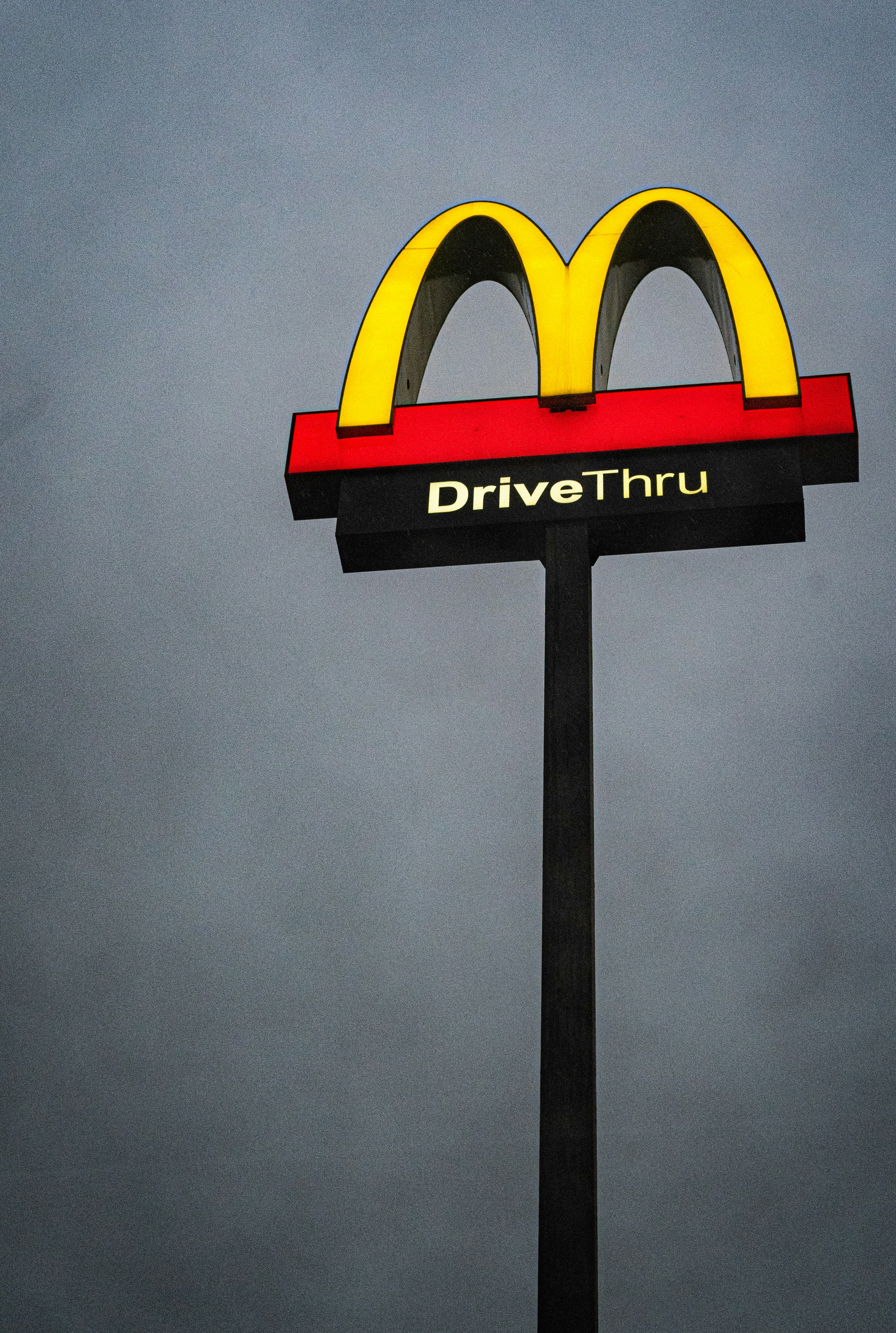 a mcdonald's drive thru sign with a cloudy sky in the background