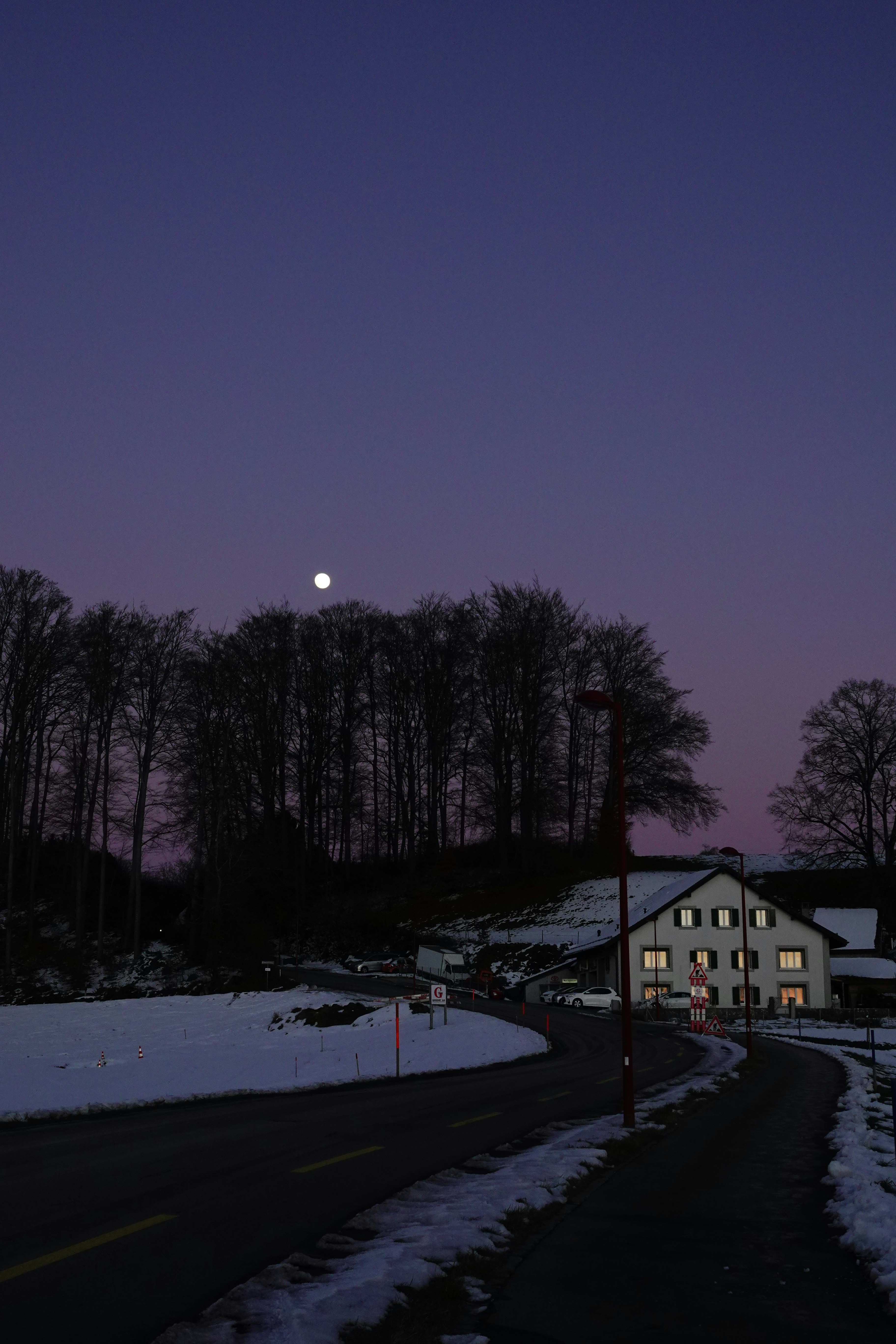 Moonlit village road under a purple winter sky