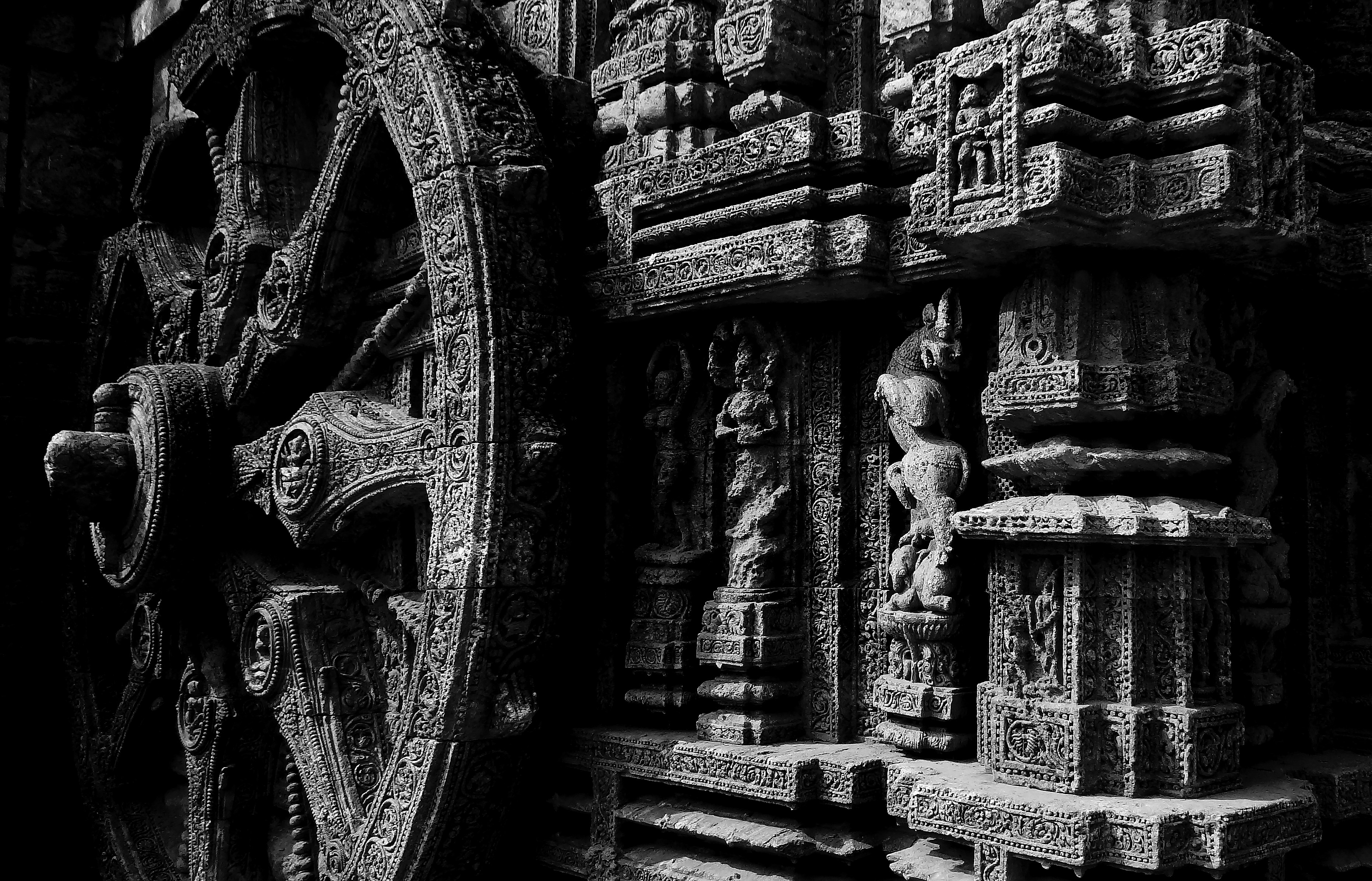 Intricately carved stone wheel adorned with detailed sculptures, showcasing the artistry of ancient architecture.