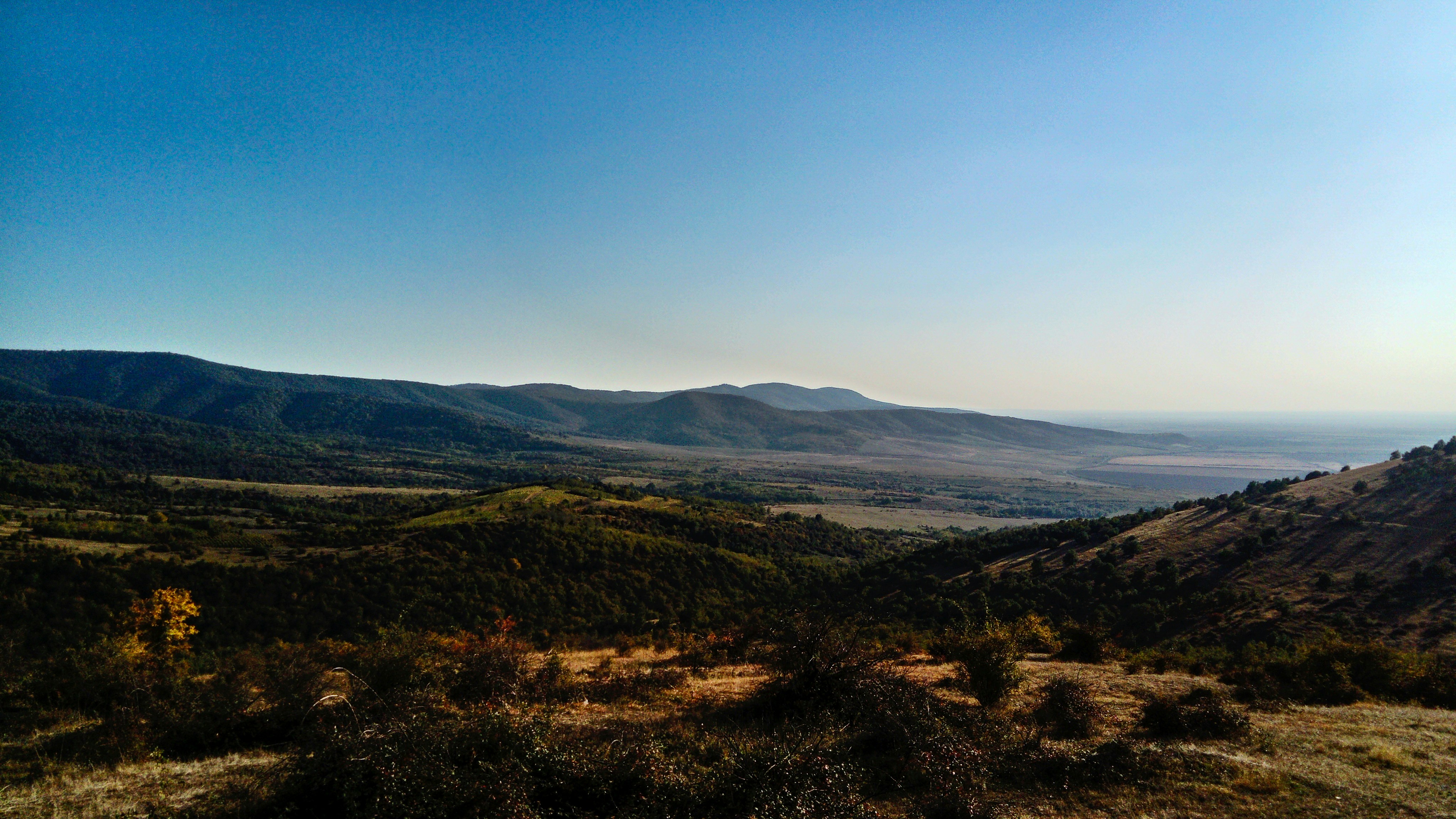 Vast landscape with rolling hills under a clear blue sky.