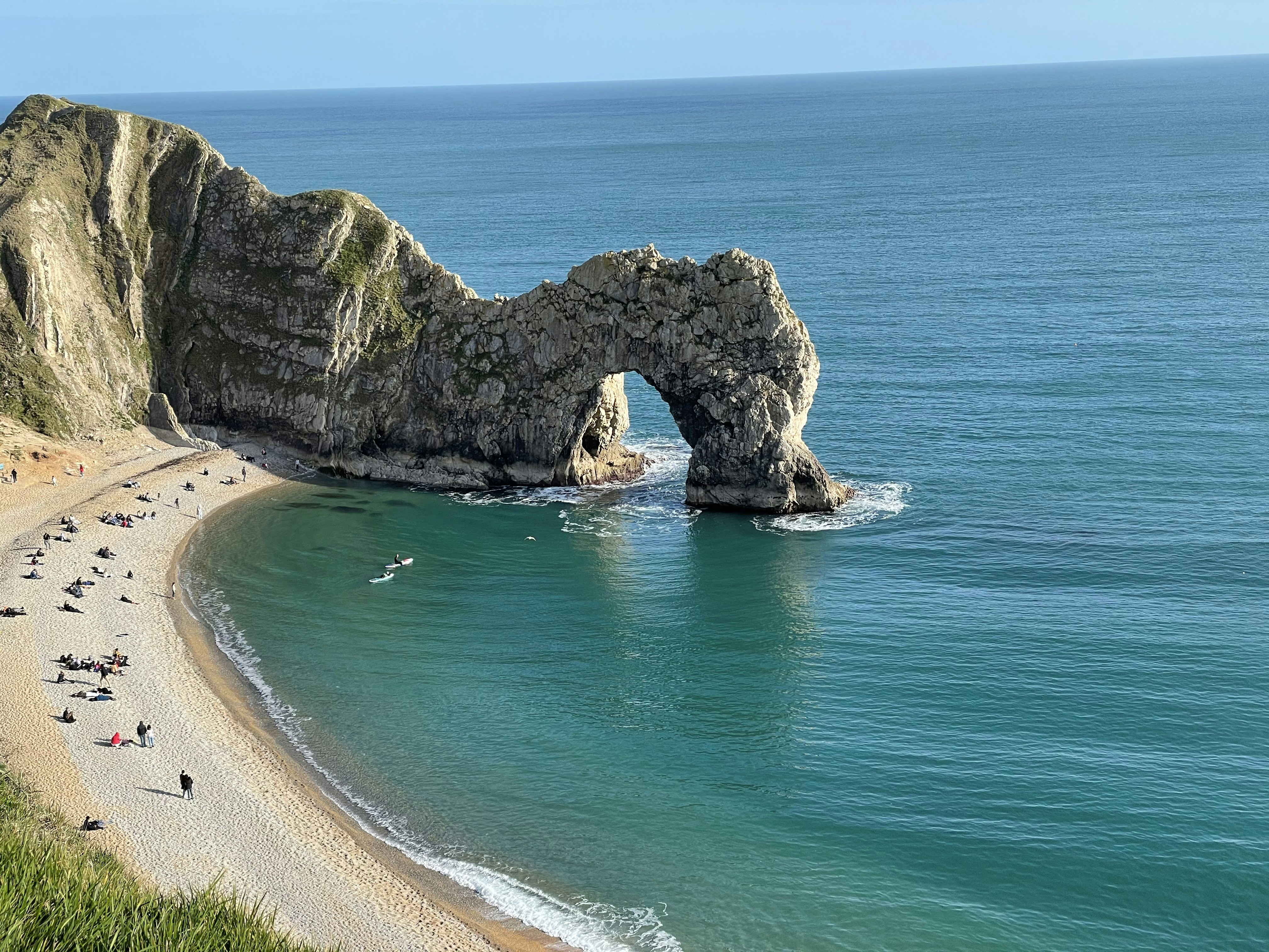 Durdle Door | a group of people standing on a beach next to the ocean