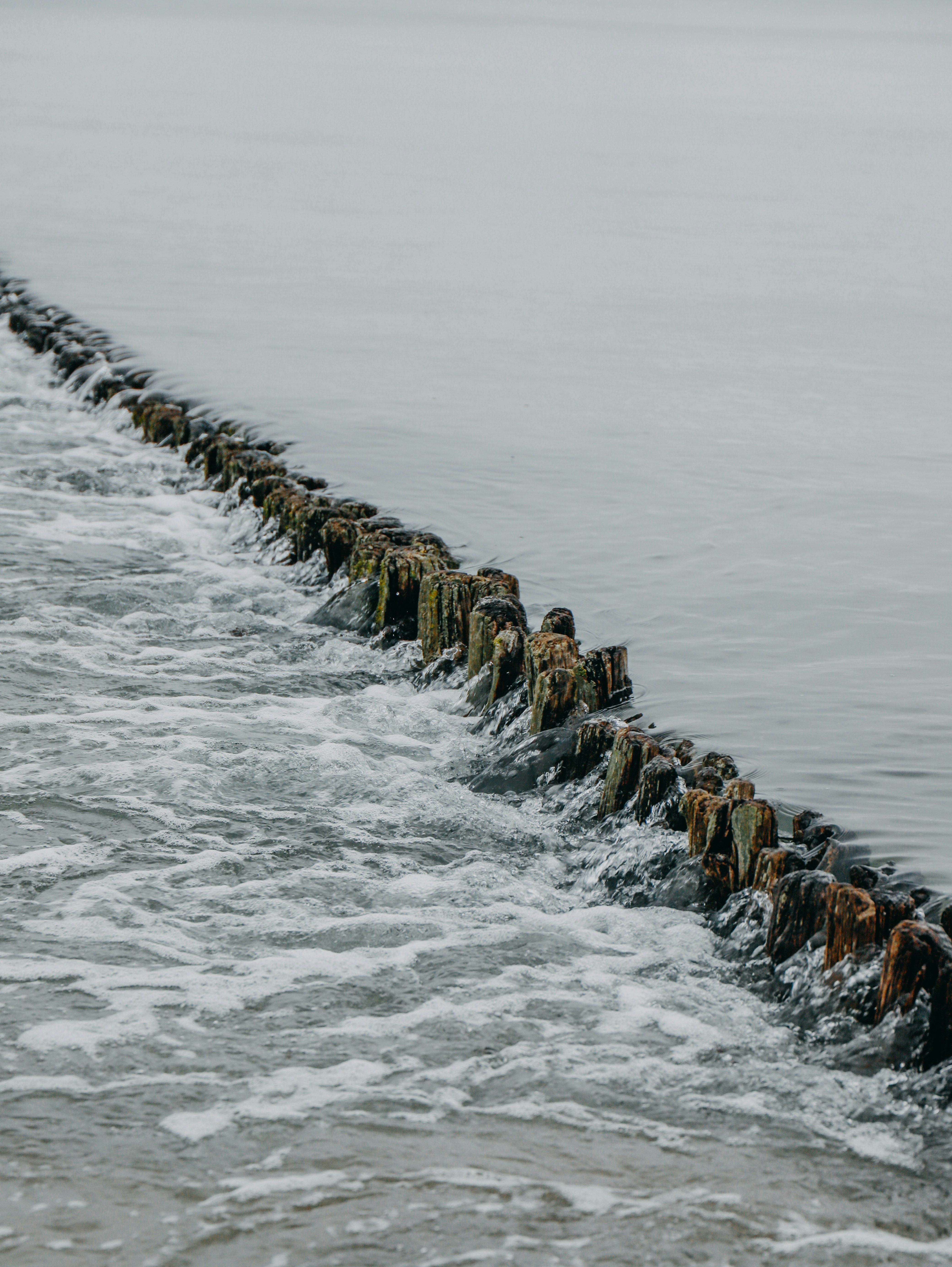 A long line of rocks sitting in the middle of a body of water photo ...
