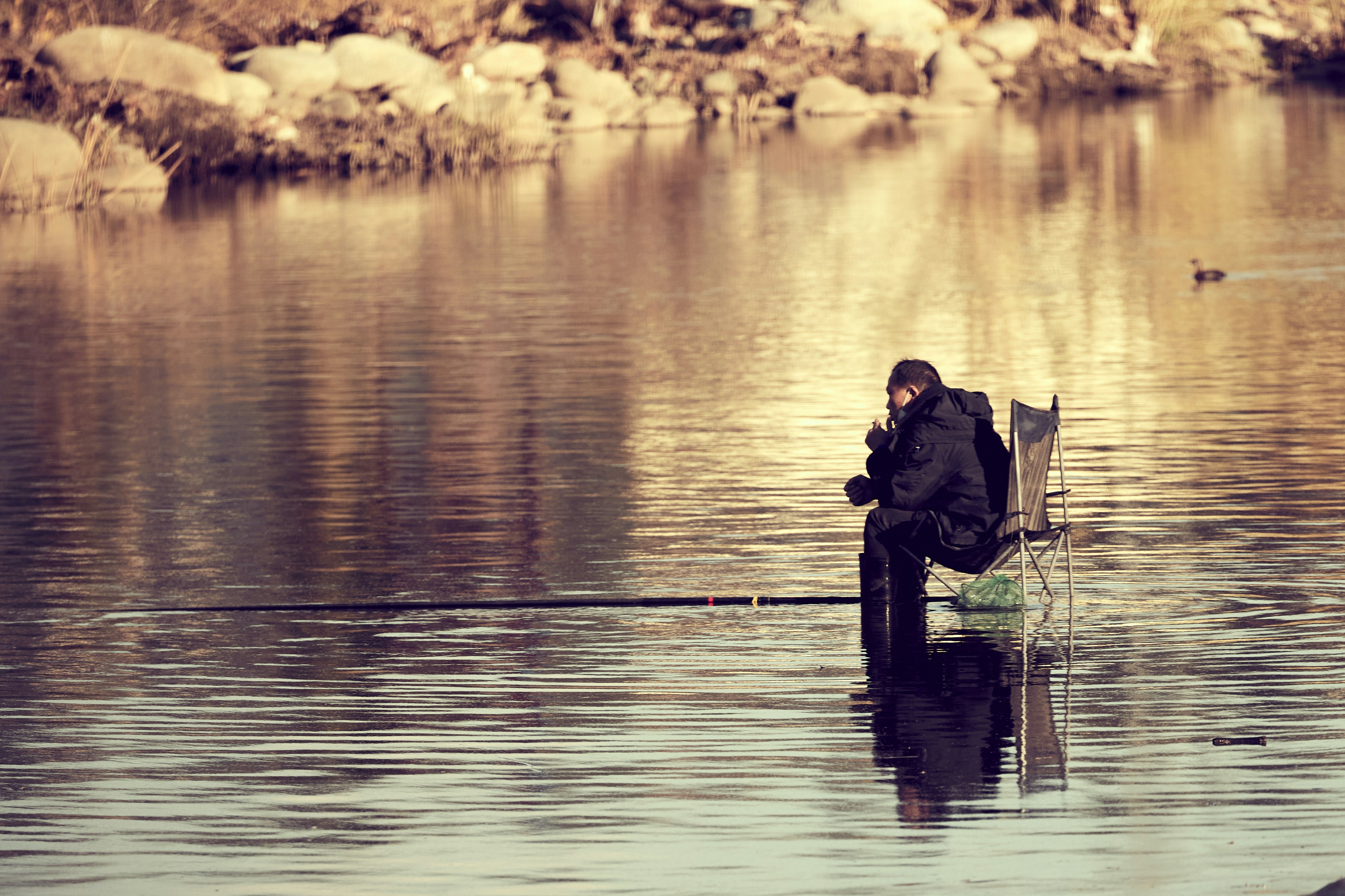 Stillness on the Distant Shore: A Lone Angler in Quiet Tint