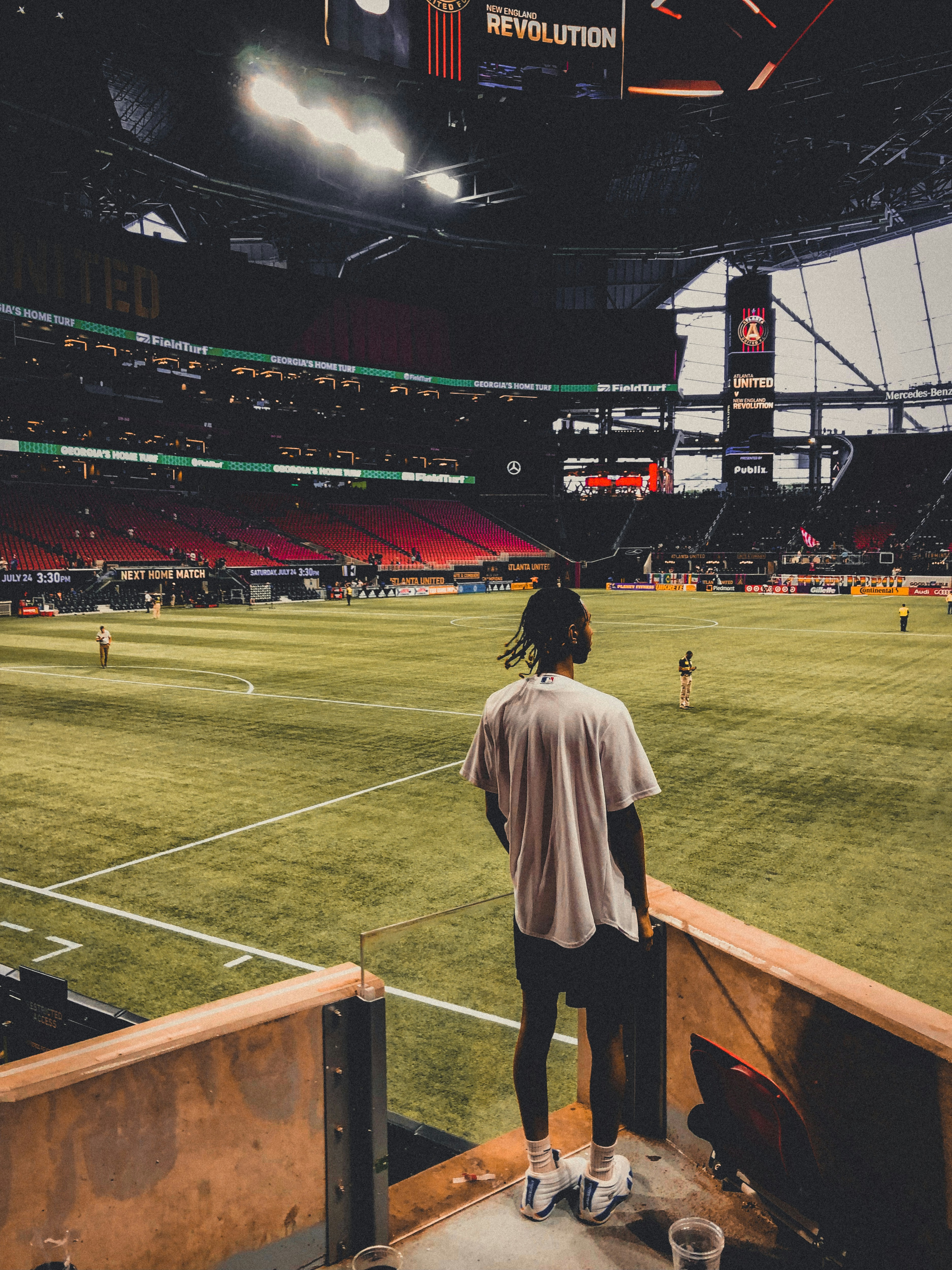 Individual gazing at a vibrant soccer field from the stadium stands.