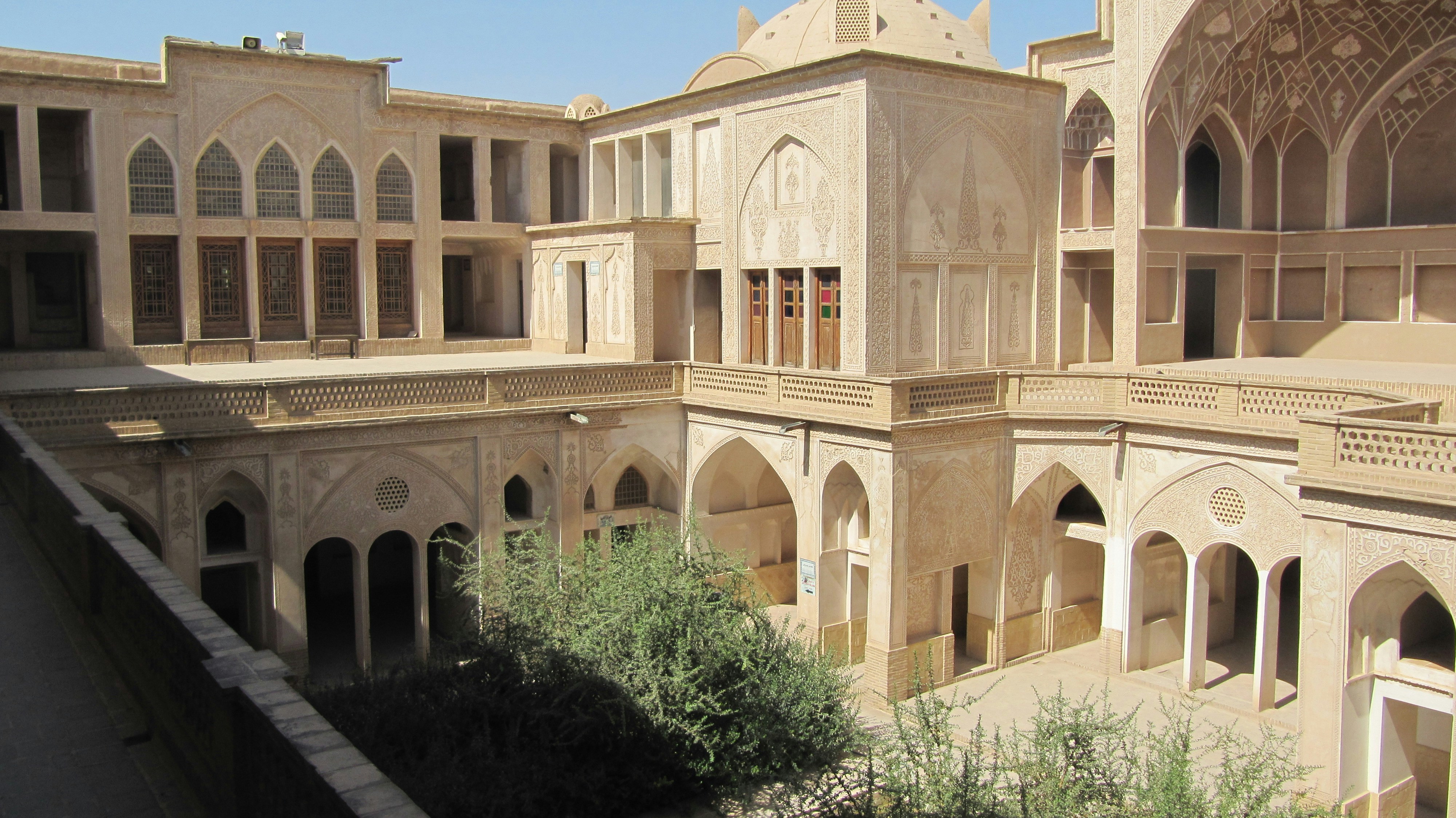 Historic courtyard with arched windows and intricate stonework under a clear blue sky.