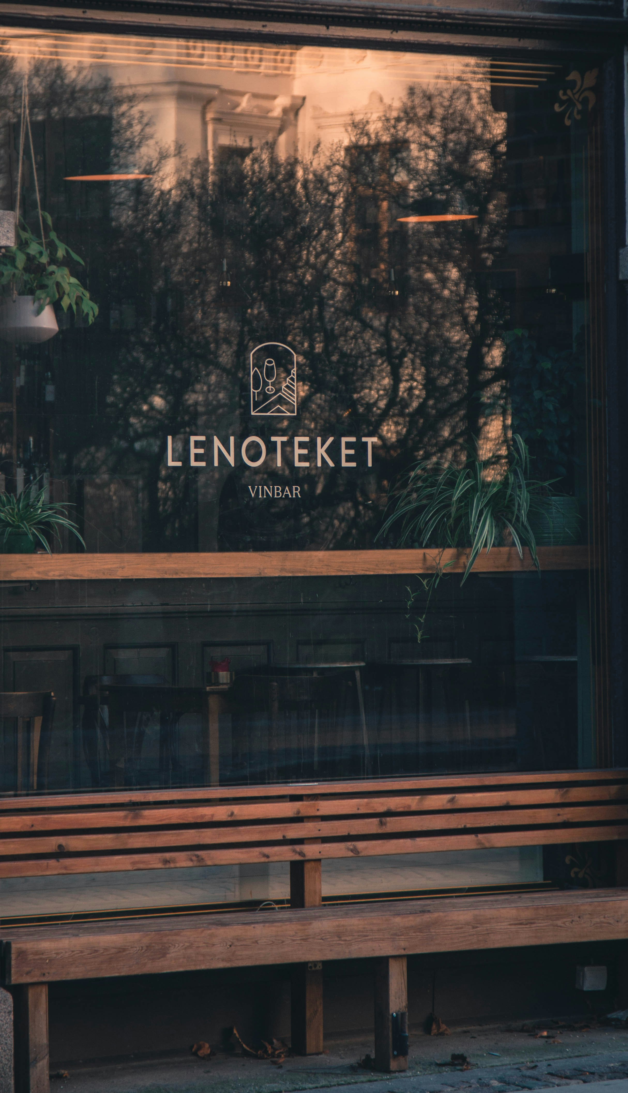 LENOTEKET Vinbar: A Glass-Front Sign Framed by Reflected Foliage