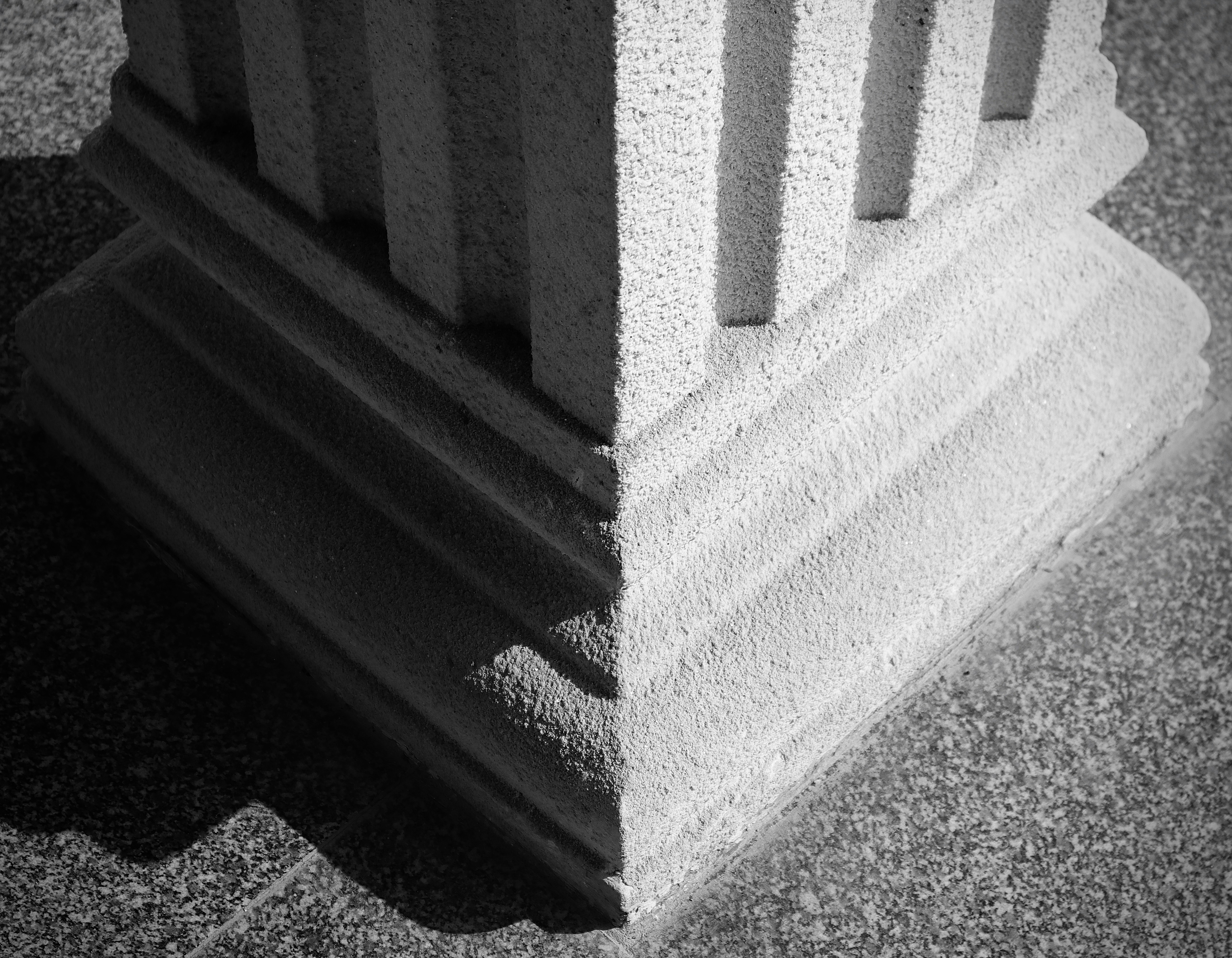 Shadowed Tiers: A Monochrome Study of a Grooved Concrete Base