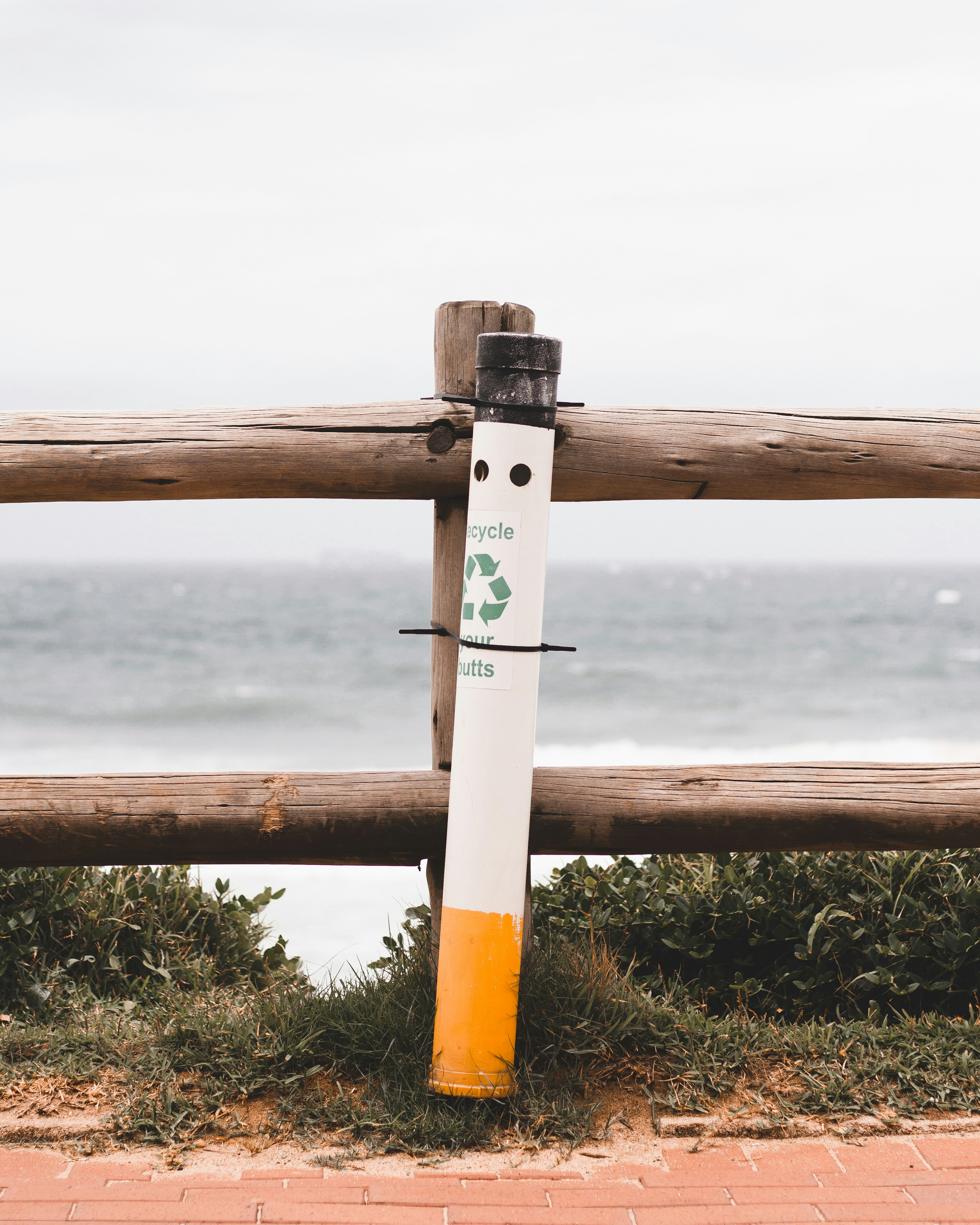 Coastal Sentinel: A White-Orange Recycling Post Framing the Sea