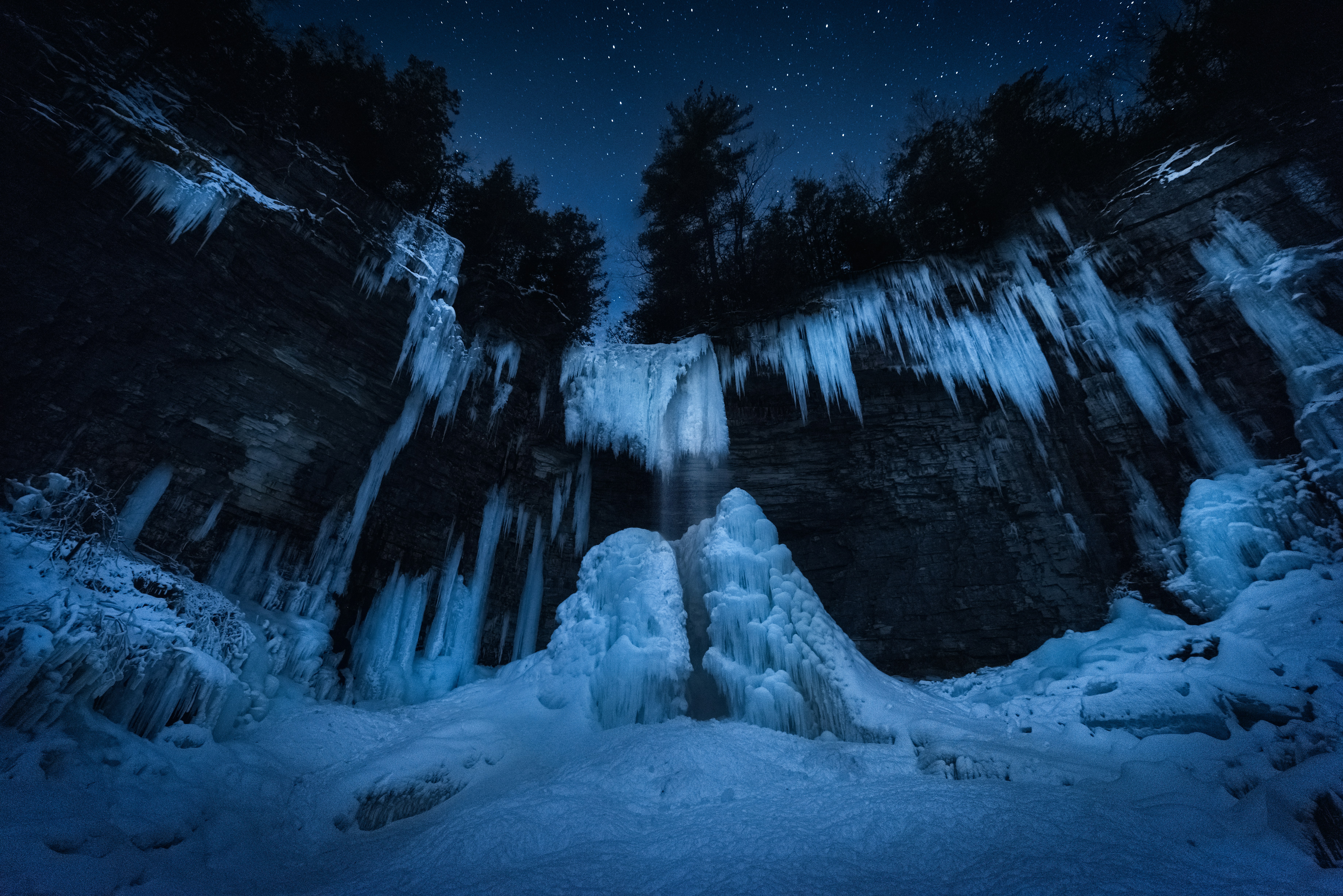 A frozen waterfall with icicles on it at night photo – Free Moonlight ...