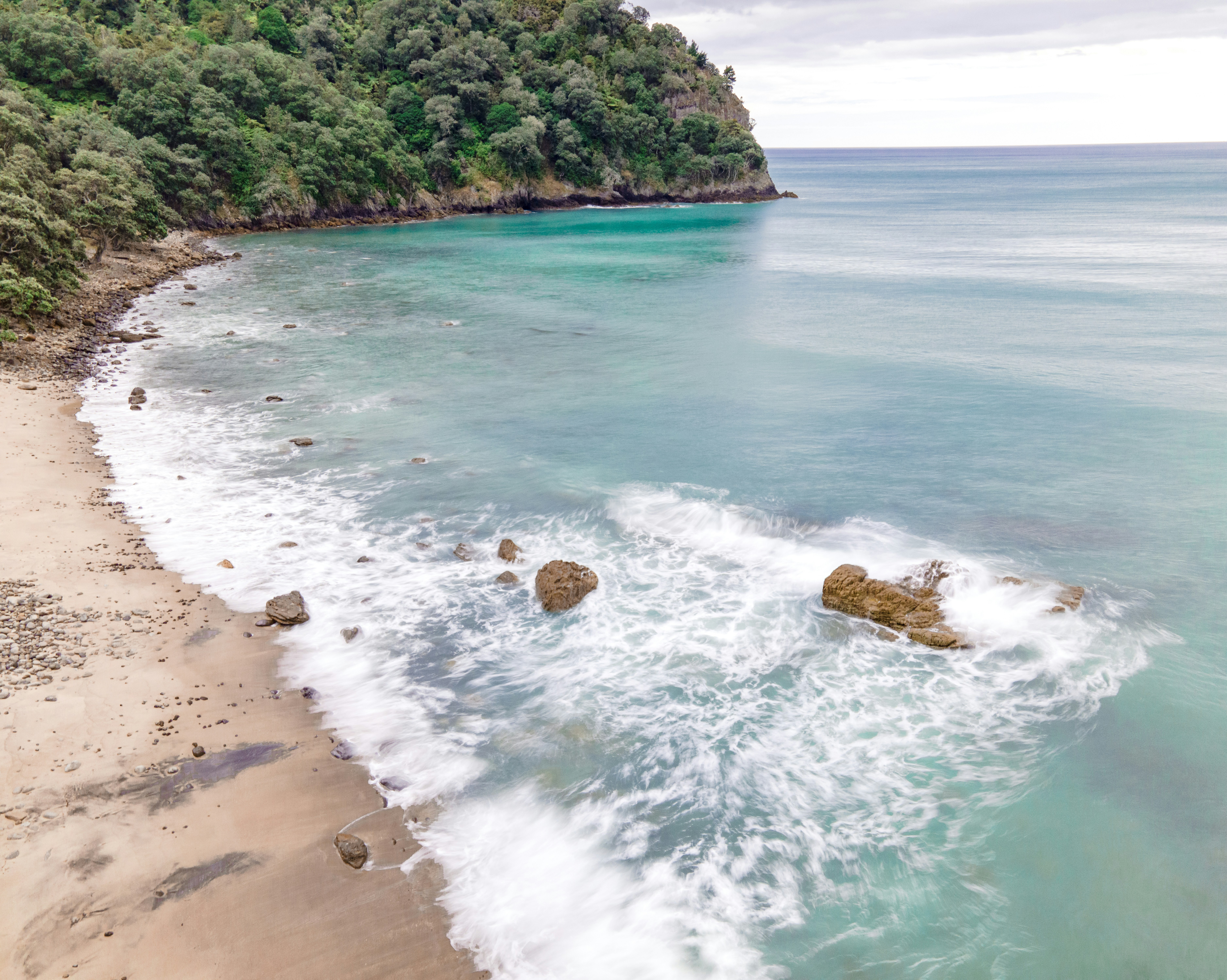 An aerial view of a beach with waves crashing on the shore photo – Free ...