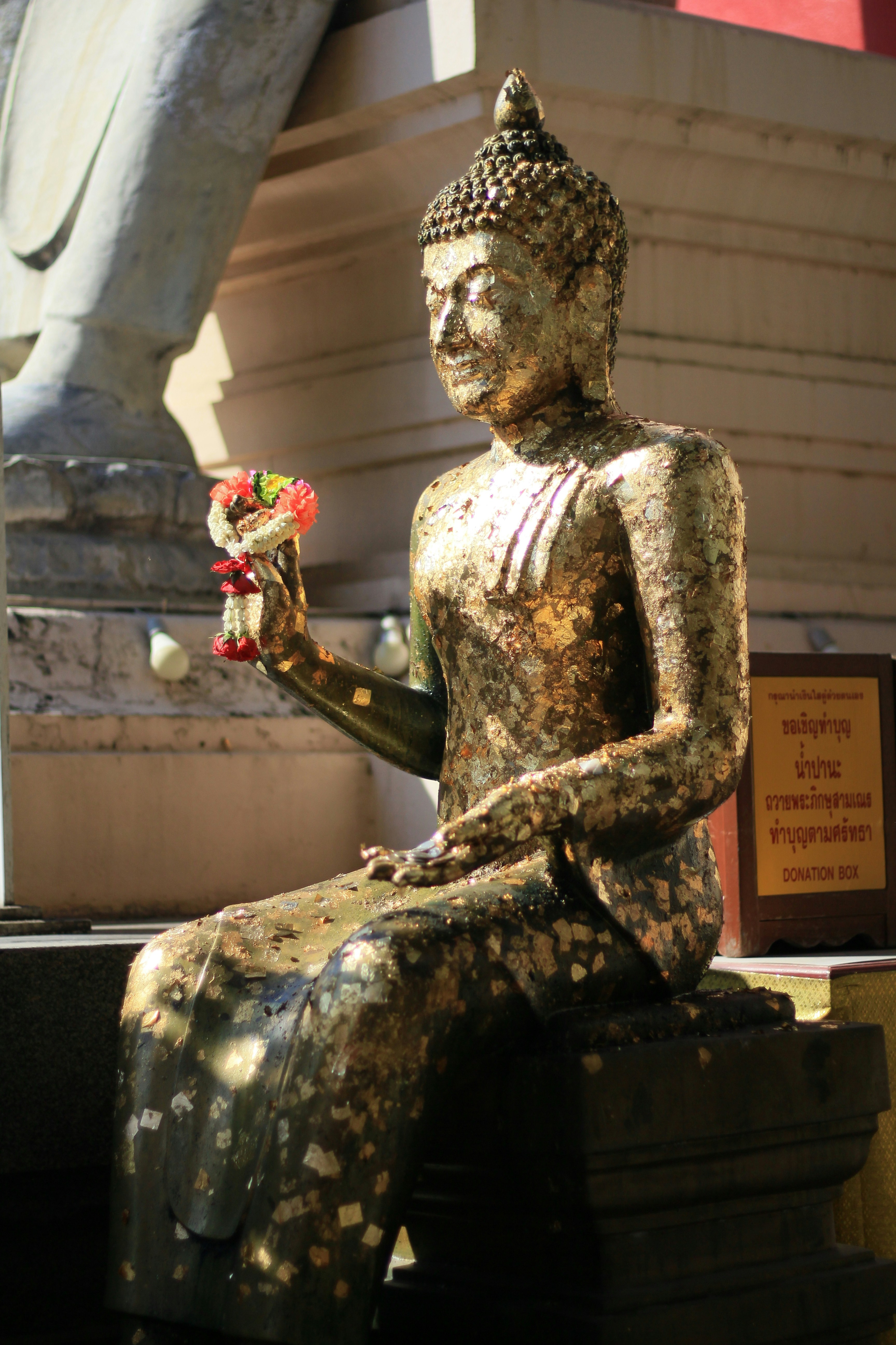 Sunlit Buddha on Weathered Steps: Quiet Gesture with a Flower Garland