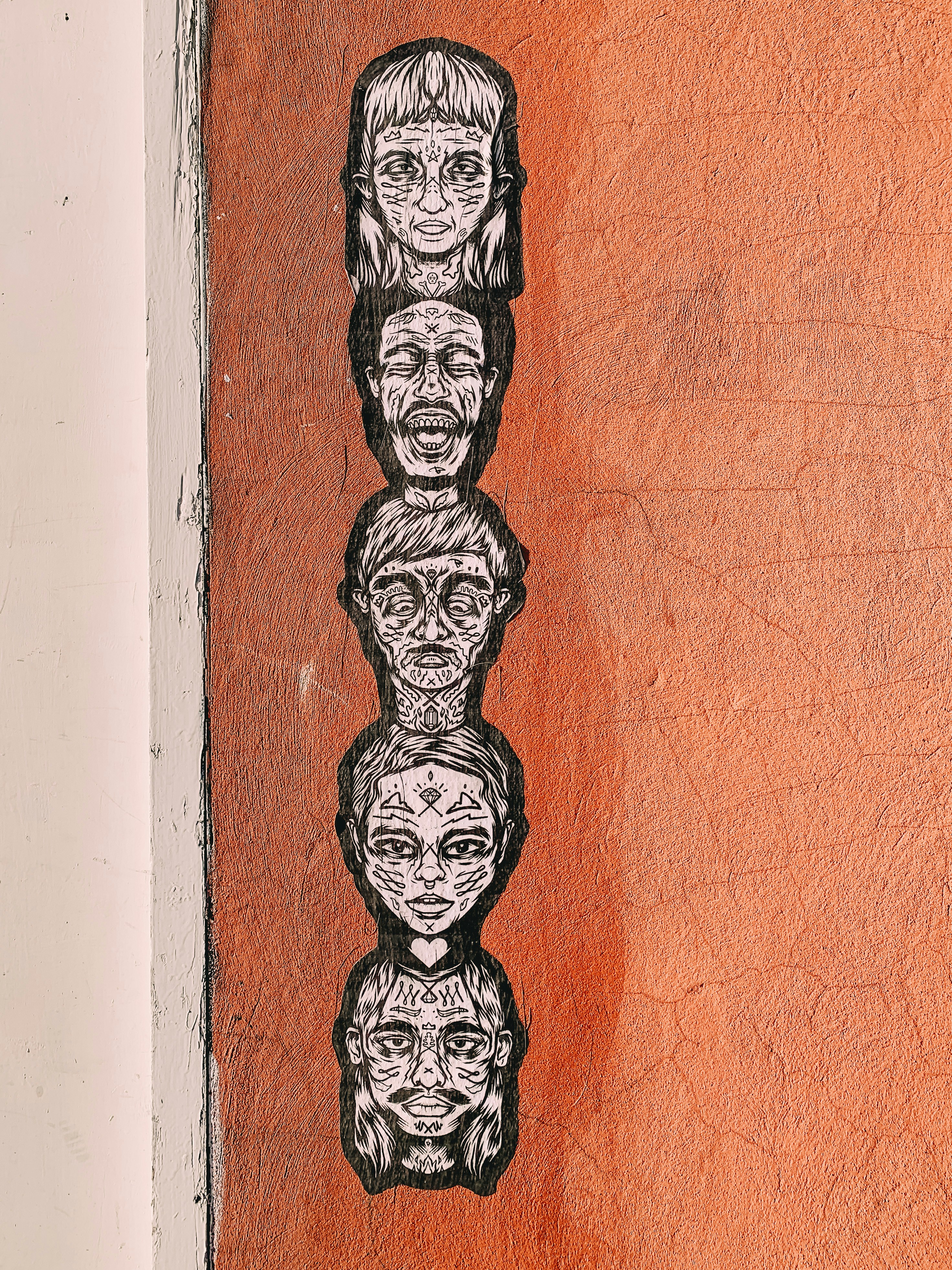 A drawing of a group of faces on a wall photo – Free Grey Image on Unsplash