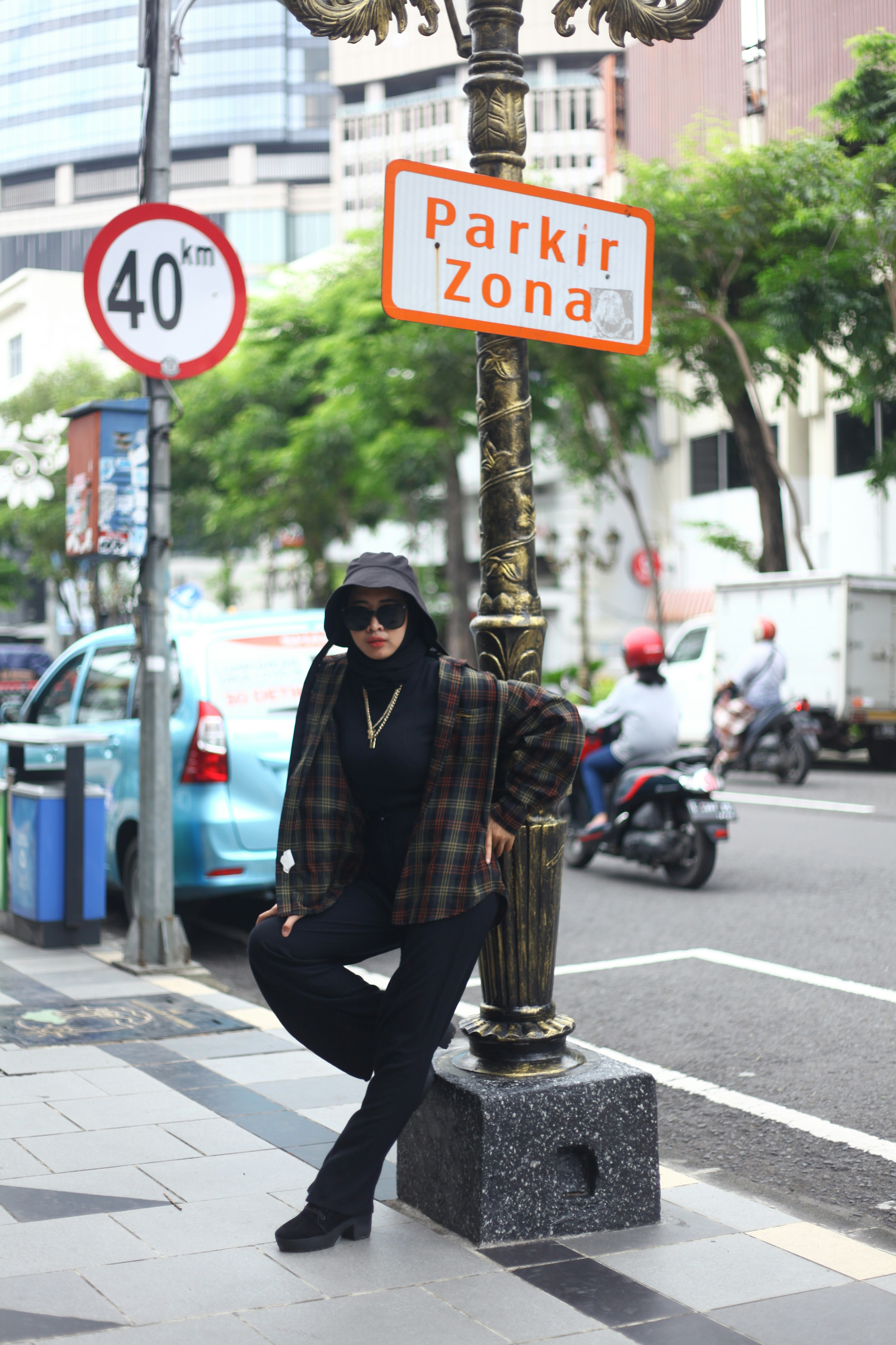 A woman leaning against a lamp post on a city street photo – Free City ...