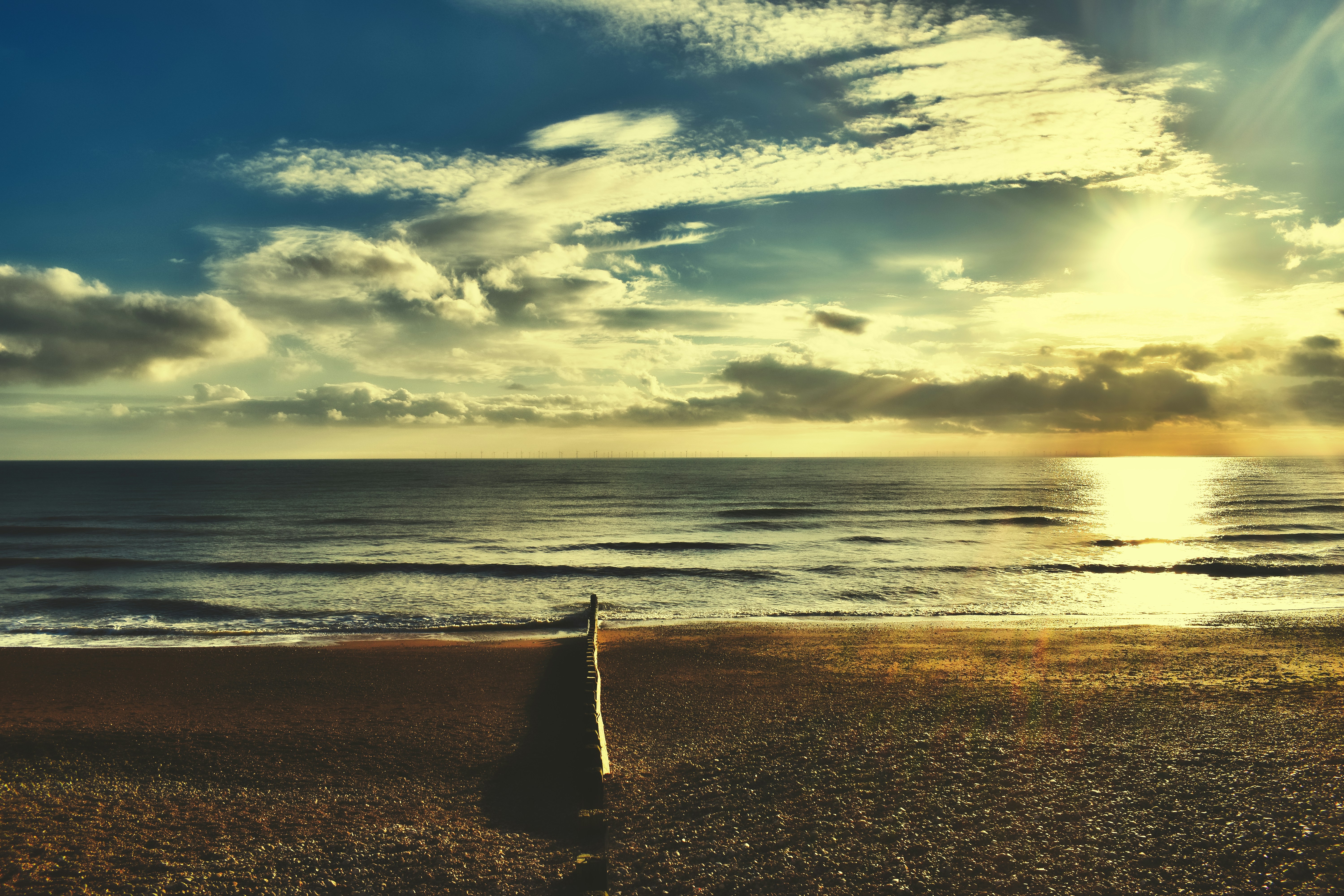 Sunlit Shoreline with Weathered Break amidst Golden Hour Clouds