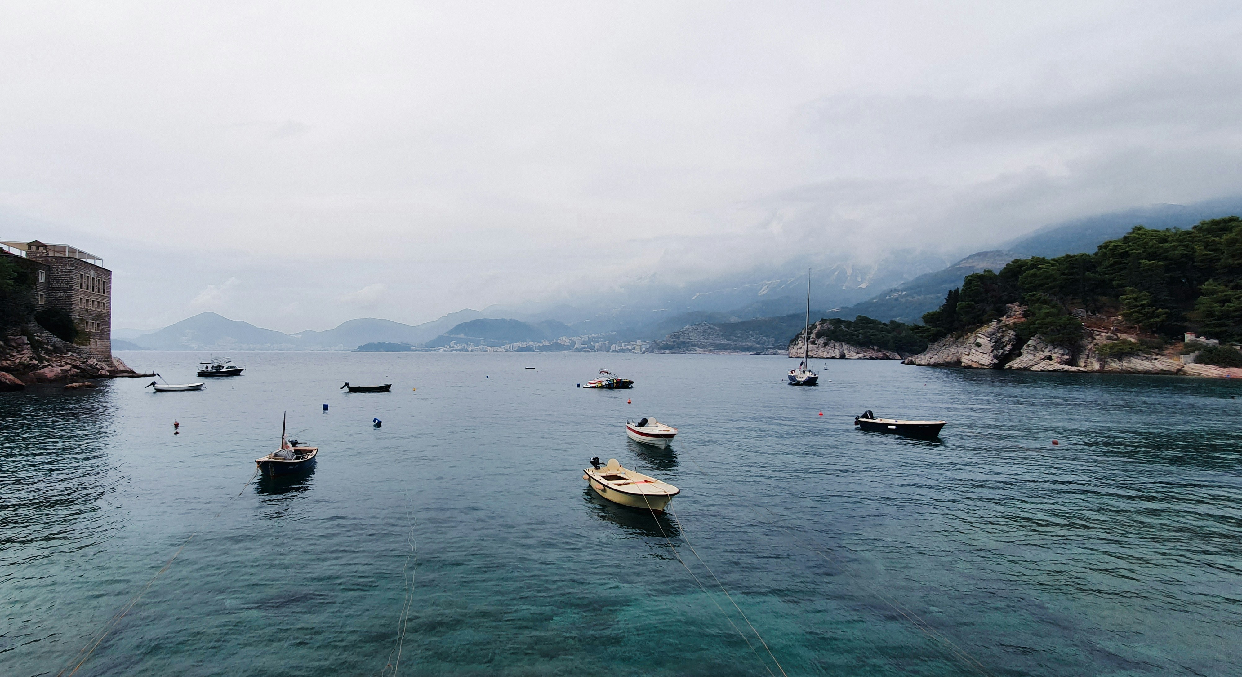 Harbor in the Mist: Boats Resting Before a Veiled Coastal Ridge
