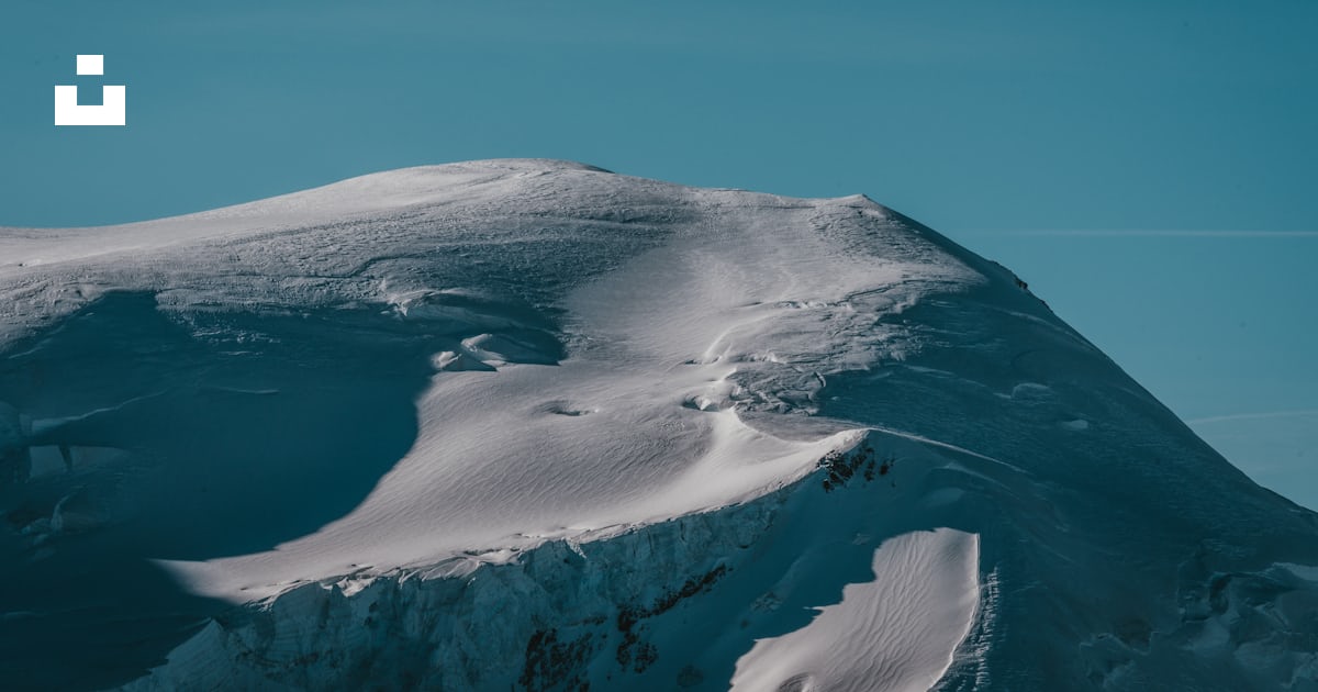 Une Montagne Couverte De Neige Sous Un Ciel Bleu Photo Photo Neiger