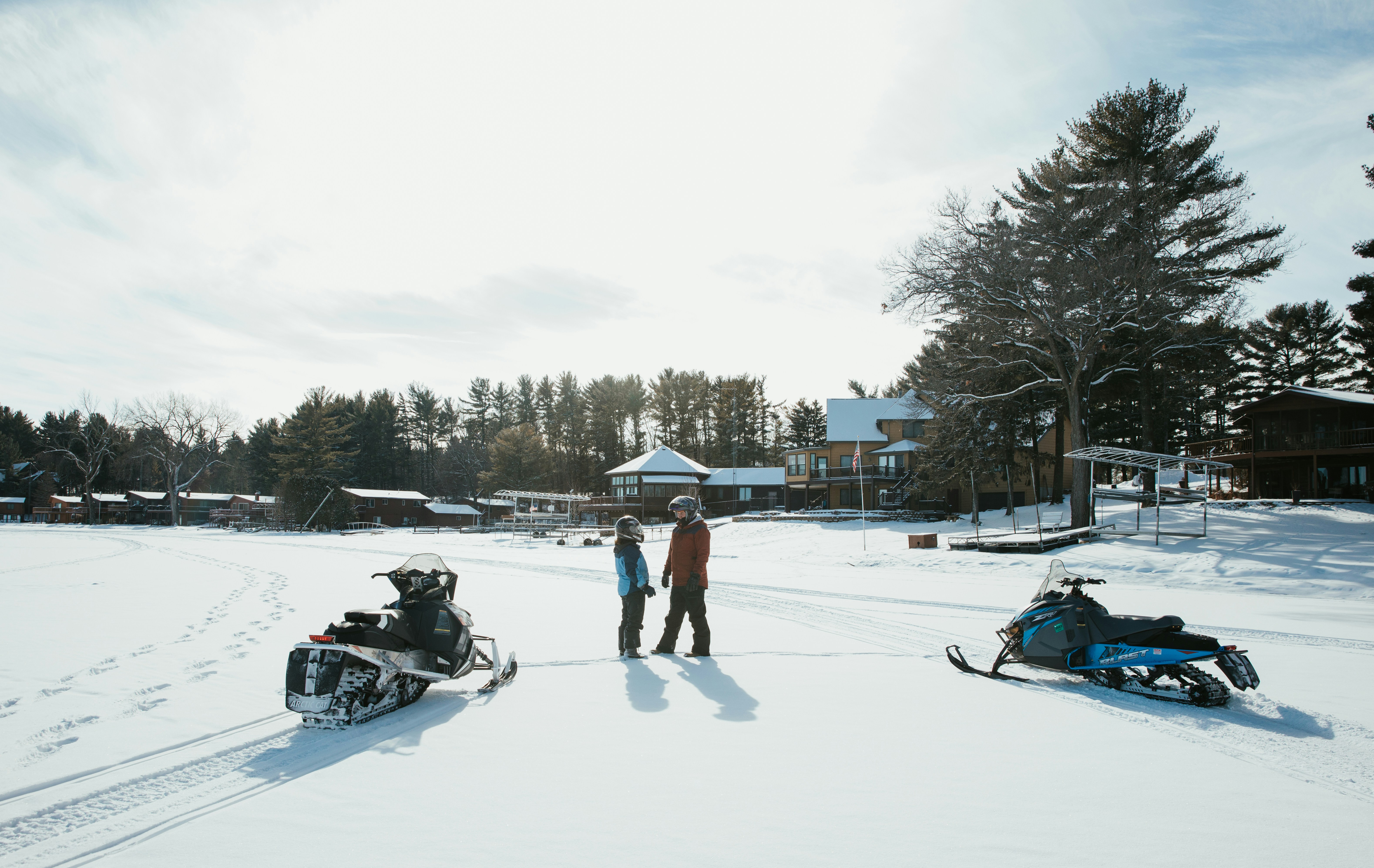 Two people standing in the snow next to snowmobiles photo – Free Lake ...