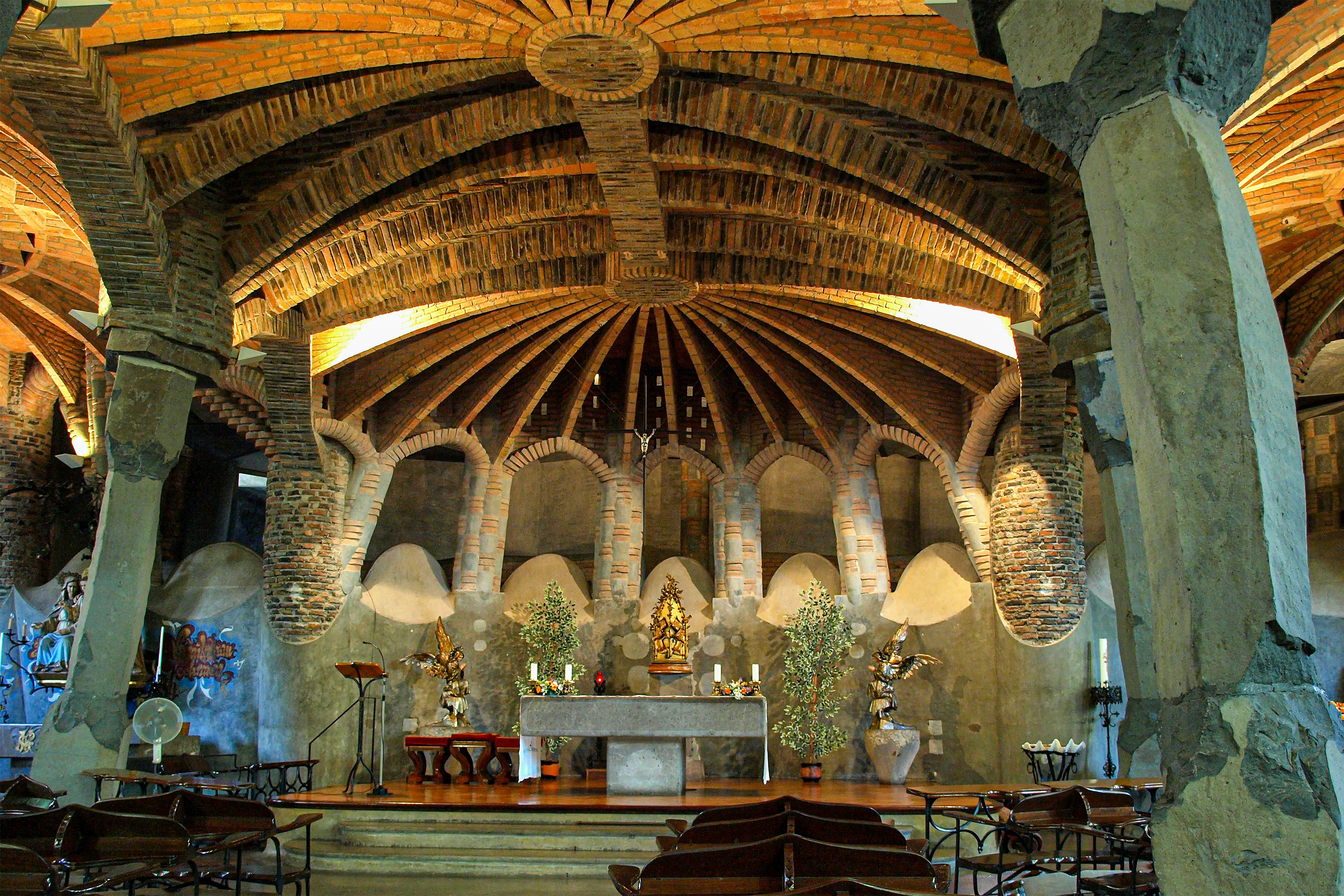 Interior view of a uniquely designed chapel featuring intricate vaulted ceilings and natural elements. The altar is adorned with greenery, blending spirituality and artistry.