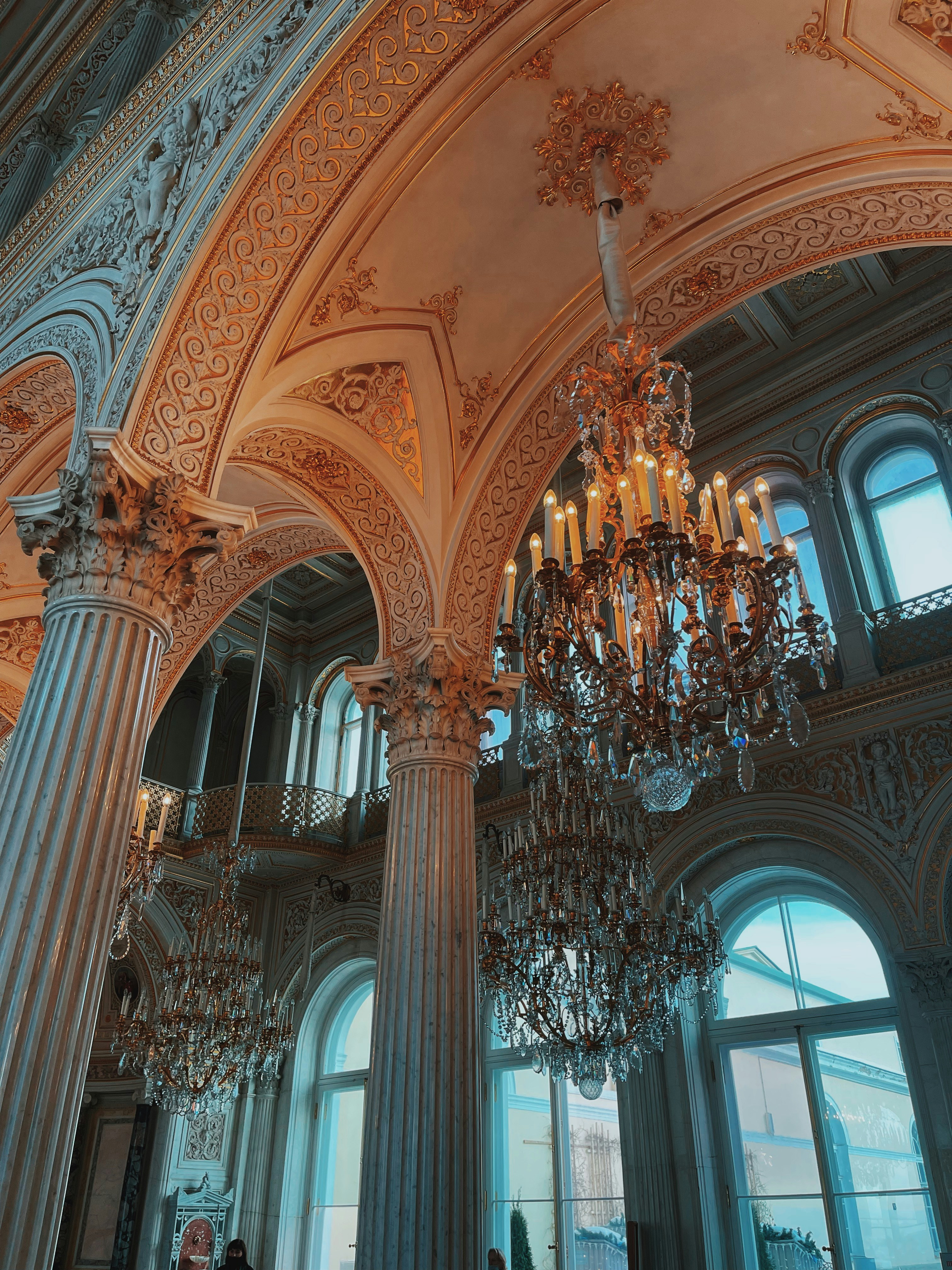 Intricate architectural details and opulent chandeliers illuminate a lavish hall, highlighting the grandeur of its design.