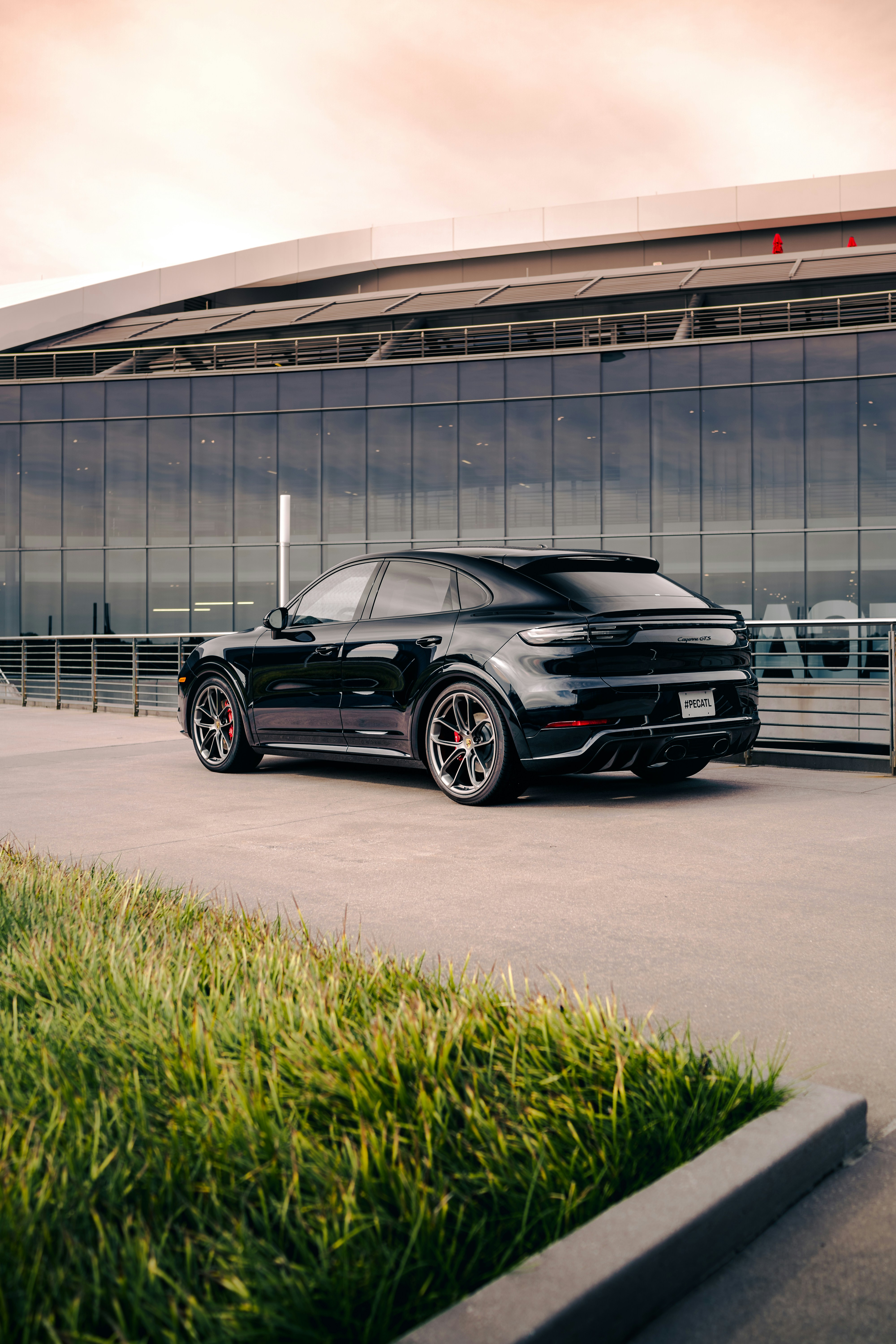 Sleek black luxury SUV parked elegantly in front of a contemporary glass building, showcasing its refined design and powerful stance.