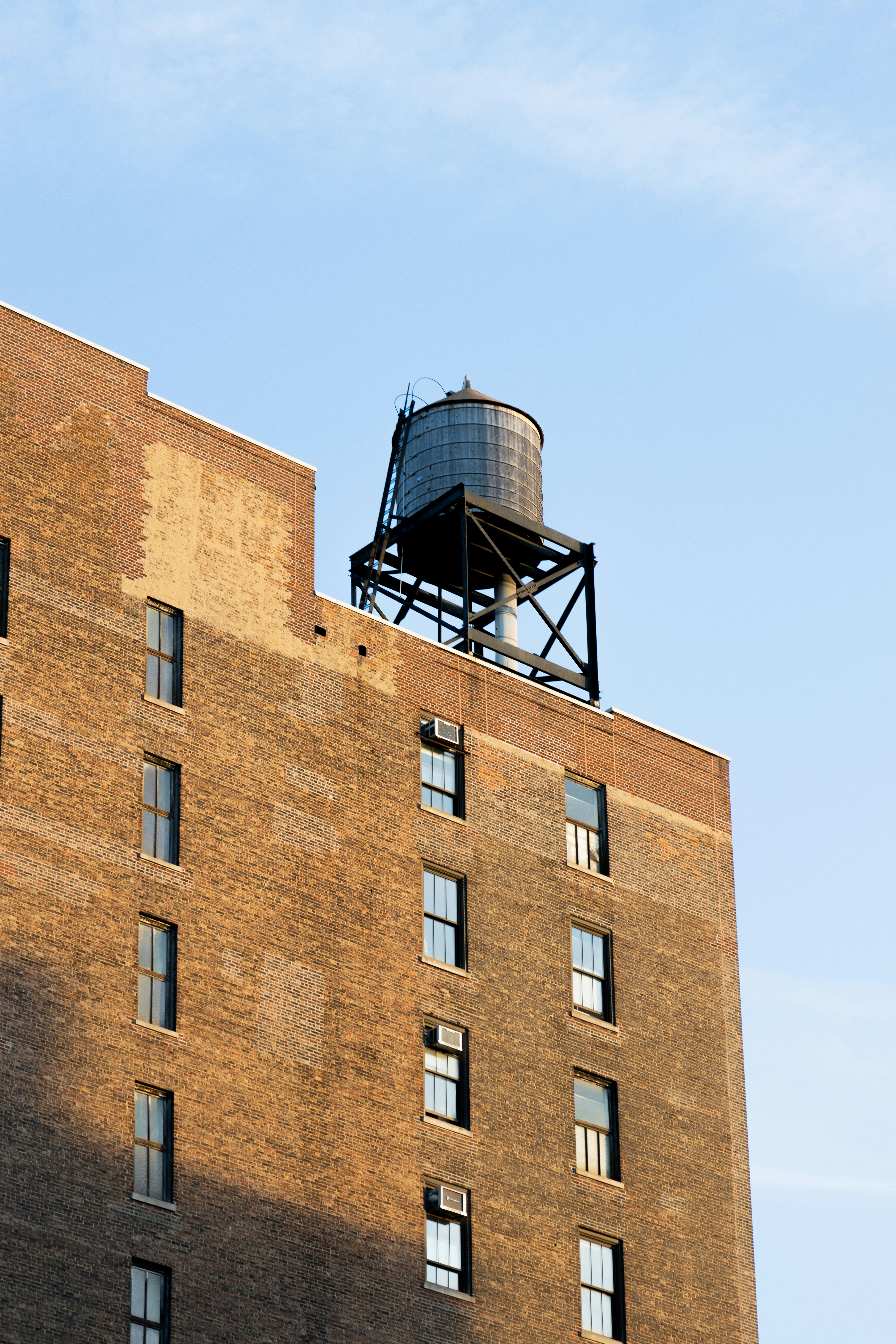 꼭대기에 급수탑이 있는 높은 벽돌 건물 사진 – Unsplash의 무료 뉴욕 이미지