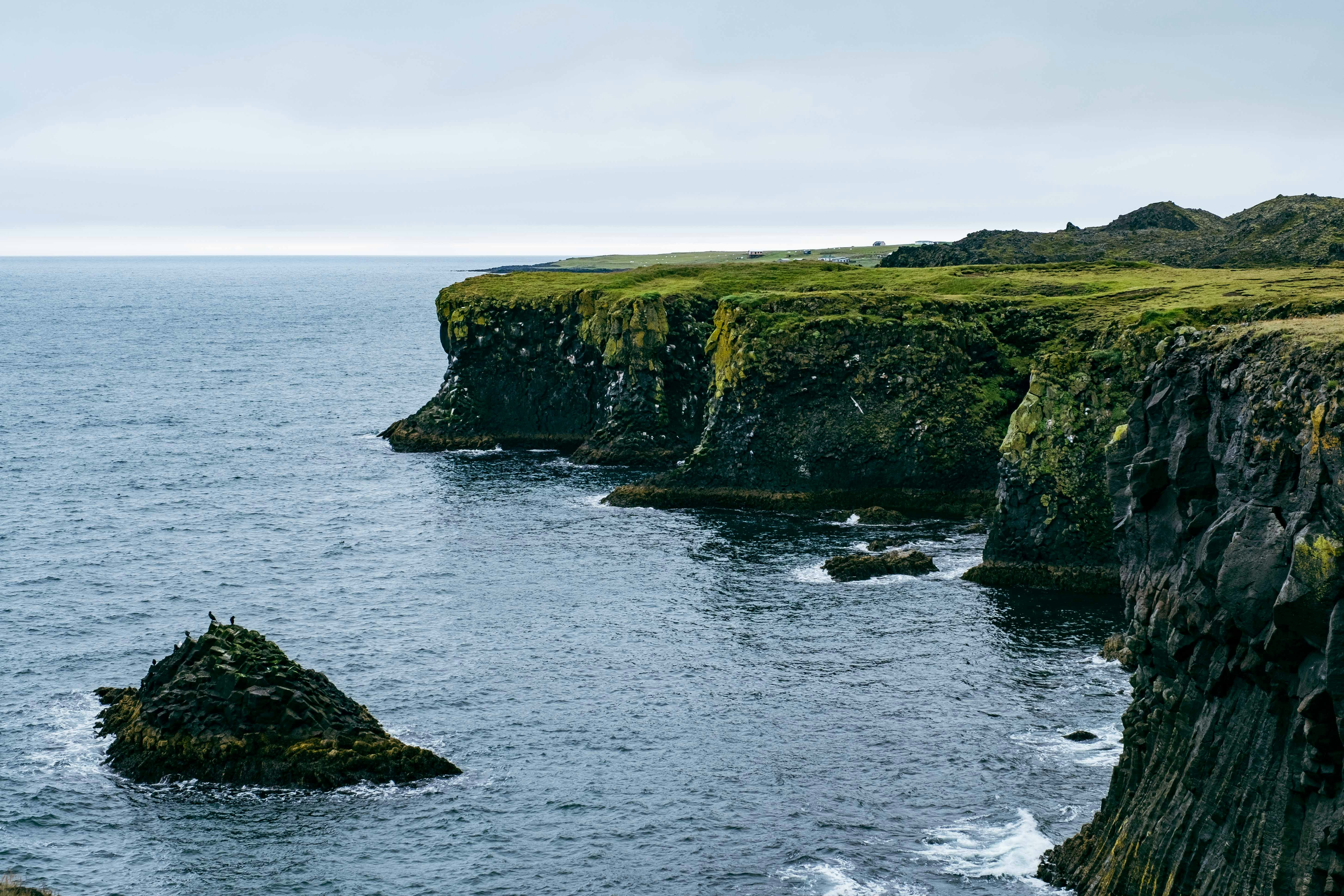 A large body of water next to a rocky cliff photo – Free Islanda Image ...