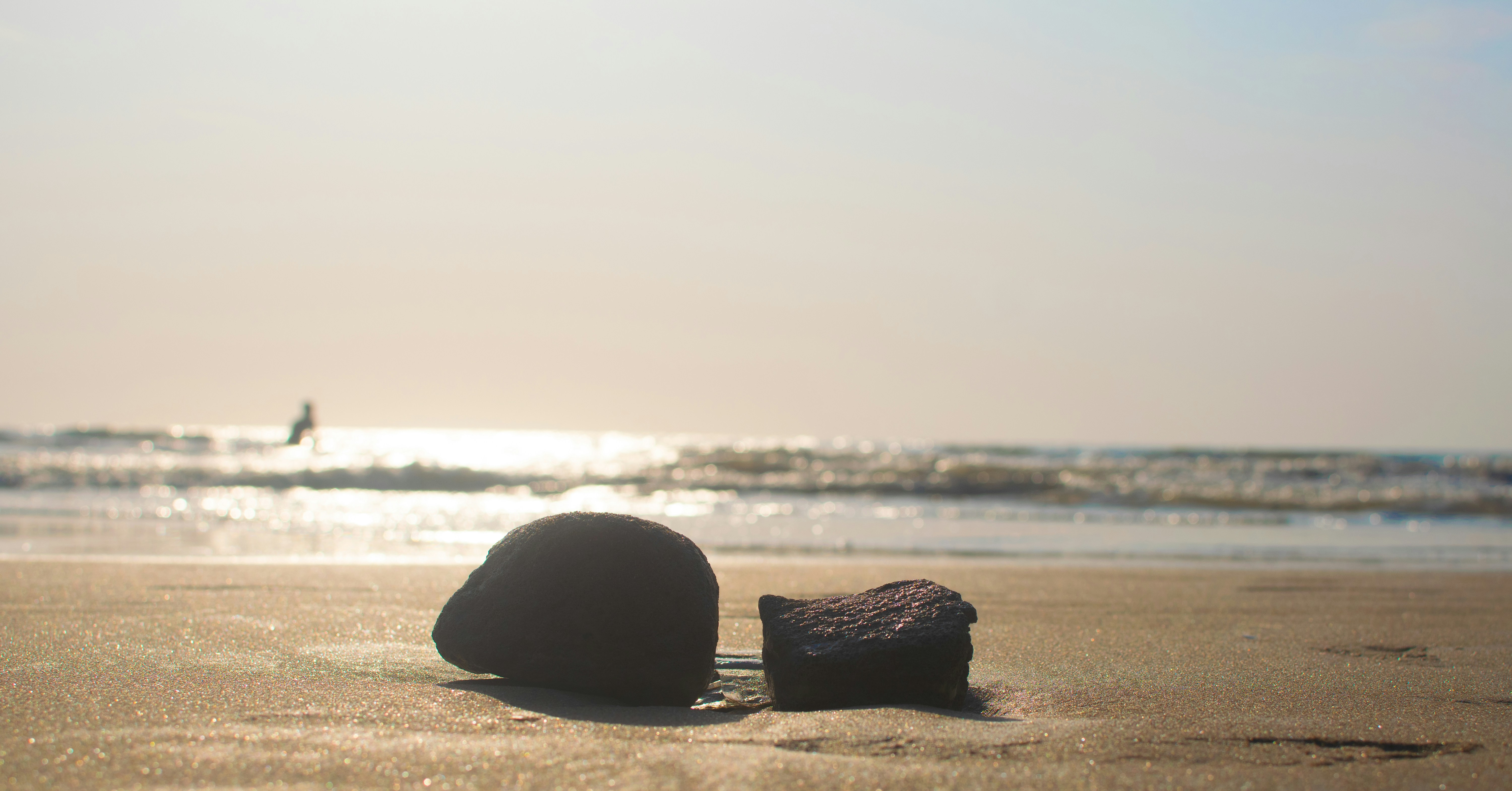 A couple of rocks sitting on top of a sandy beach photo – Free Mumbai ...