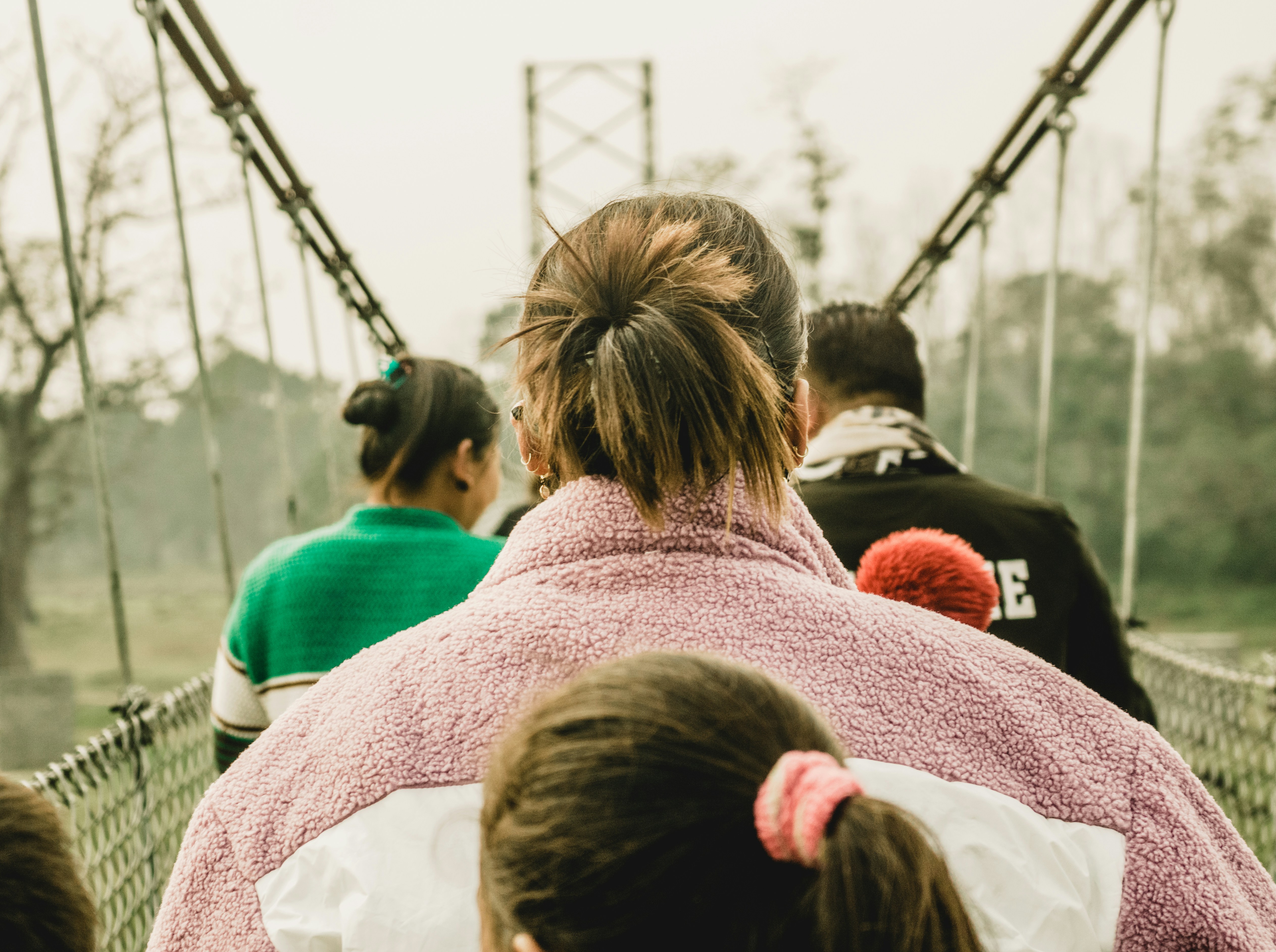 Group of individuals walking across a suspension bridge, showcasing a sense of togetherness and adventure.