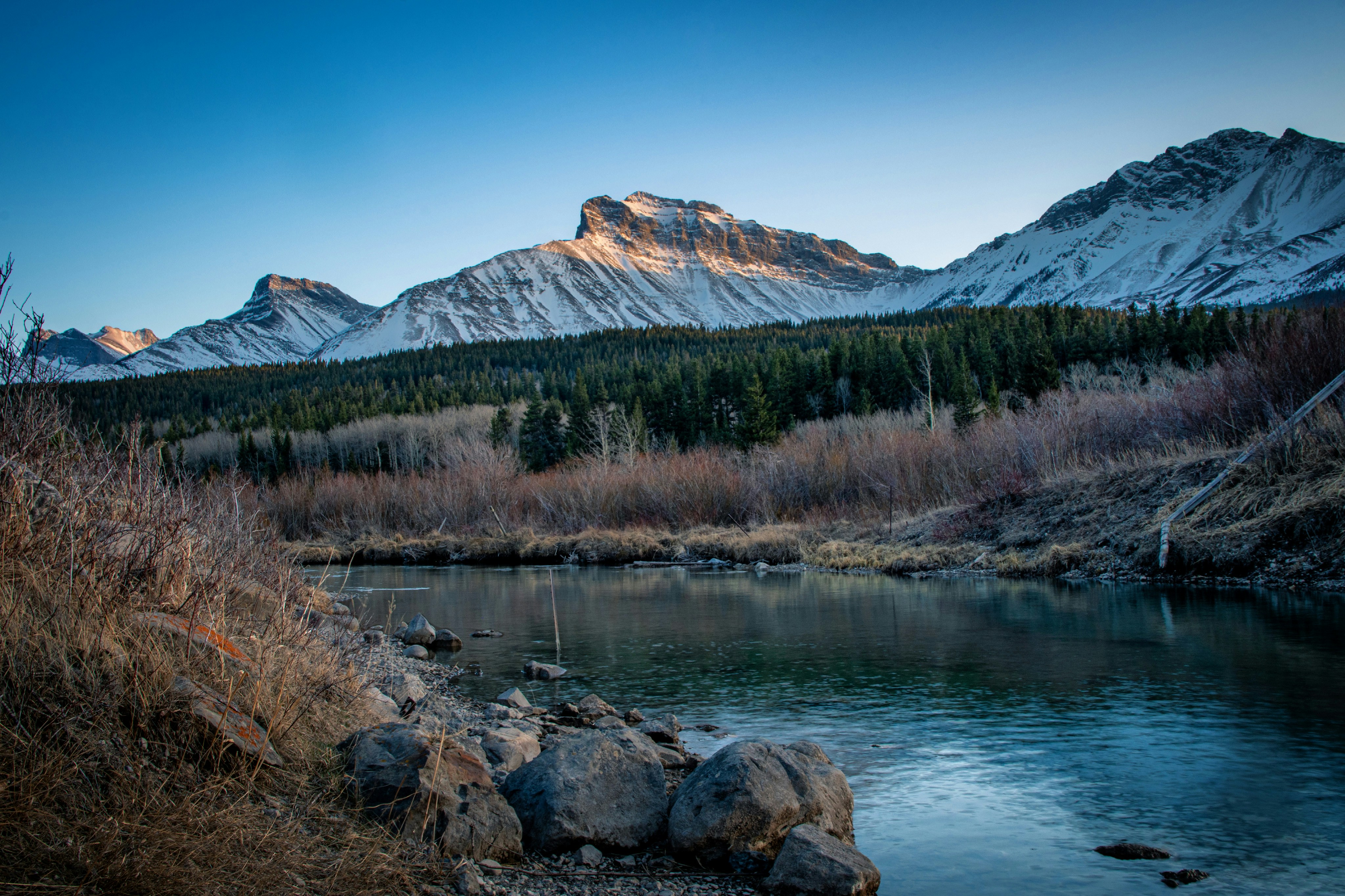 Dawn Crown Over Snow-Capped Peaks Framing a Quiet River