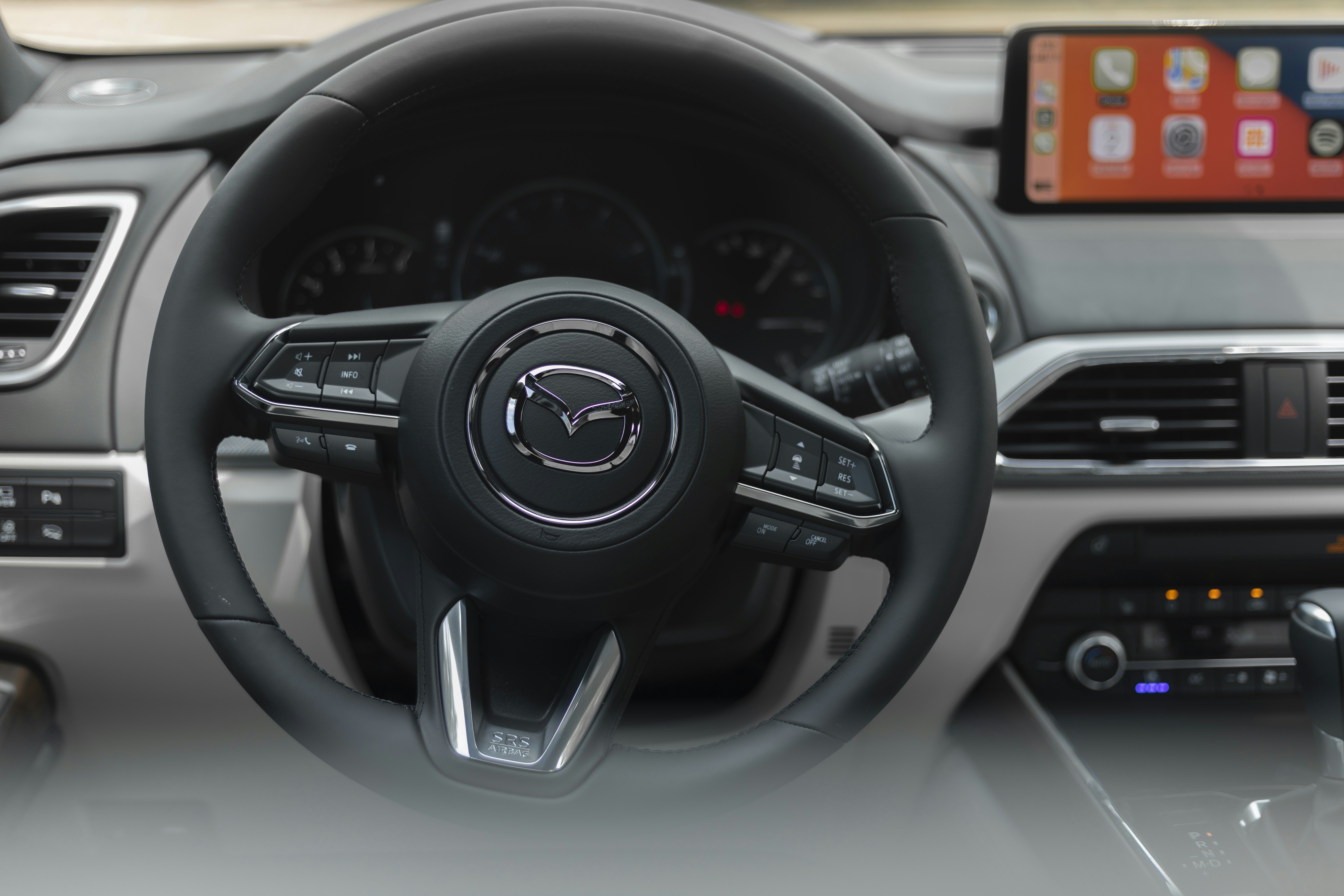 Interior view of a Mazda vehicle showcasing the steering wheel and dashboard controls. The design emphasizes functionality and modern technology.