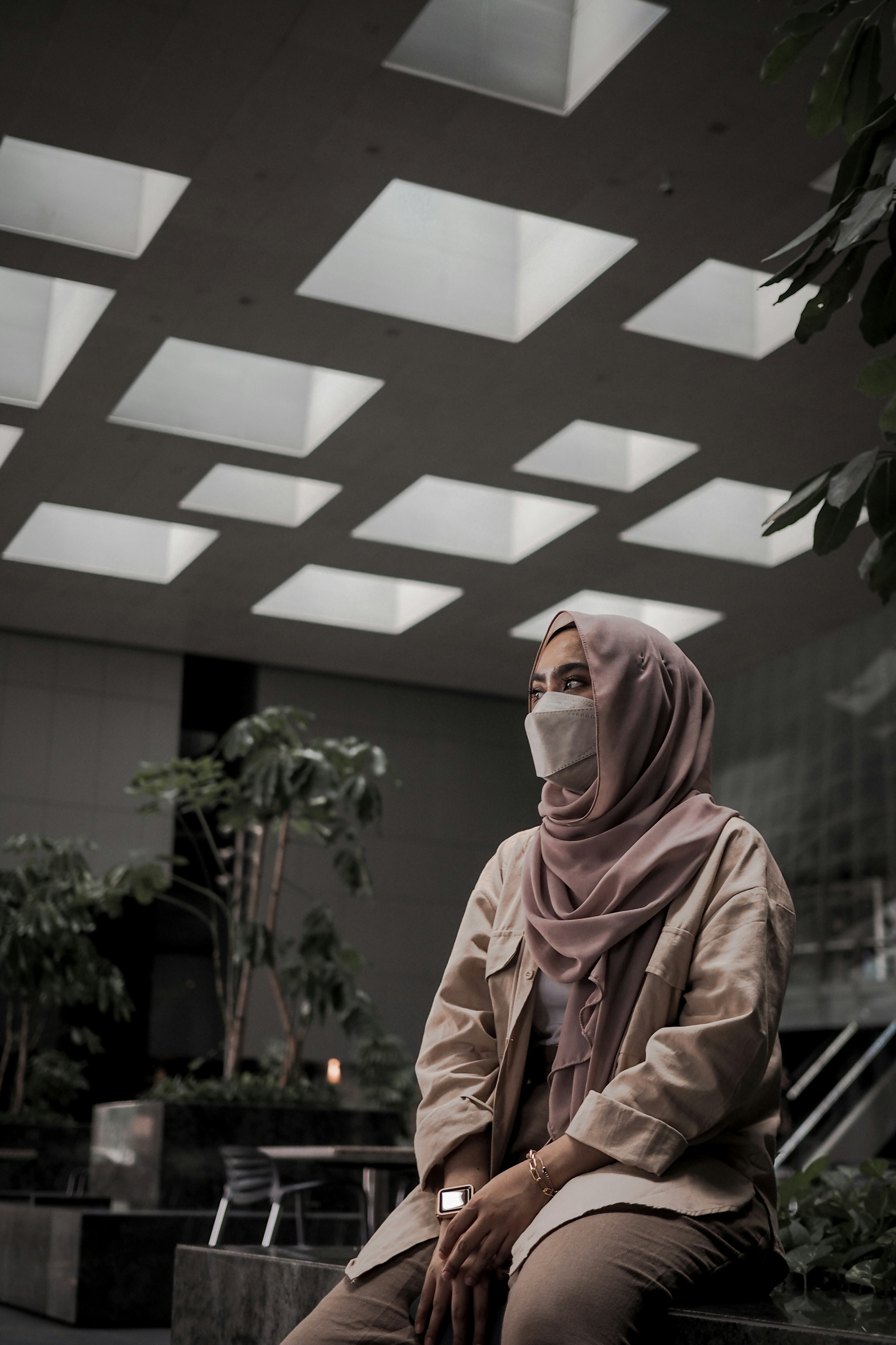 A woman wearing a face mask sitting on a bench photo – Free Clothing ...