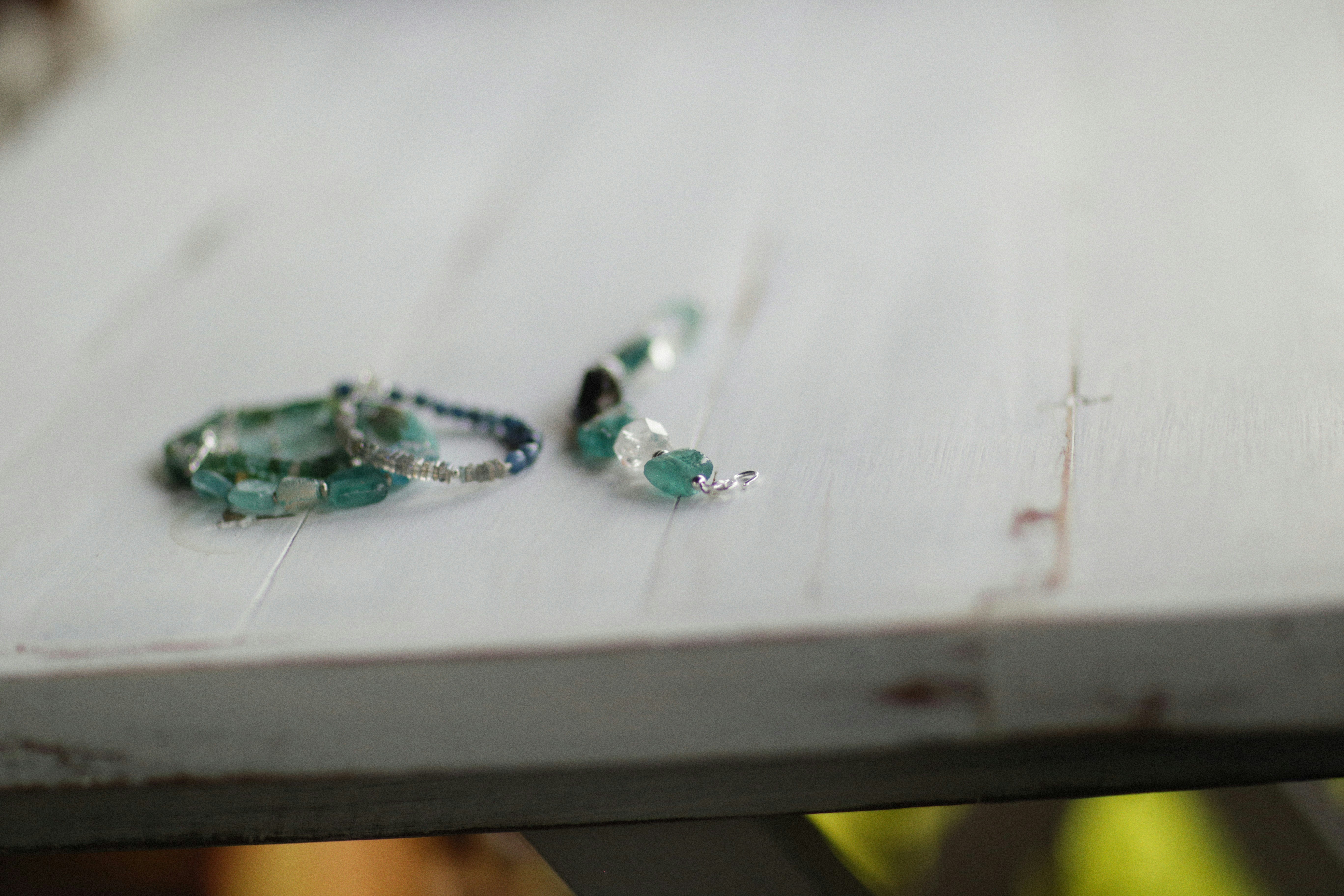 Teal Gem Beadwork on a Weathered White Table
