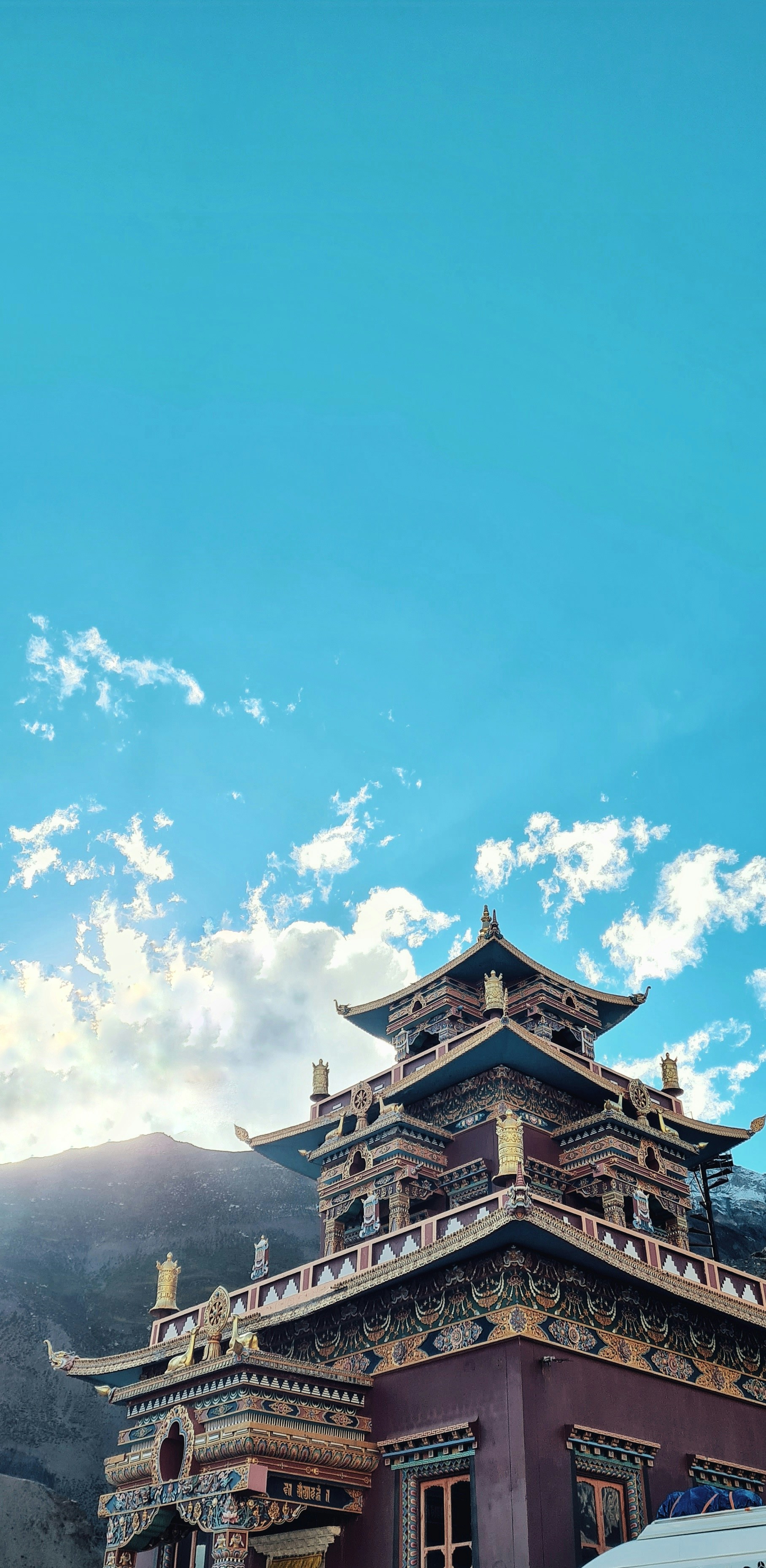 Intricately designed temple structure against a bright blue sky with wispy clouds, showcasing architectural beauty and cultural significance.