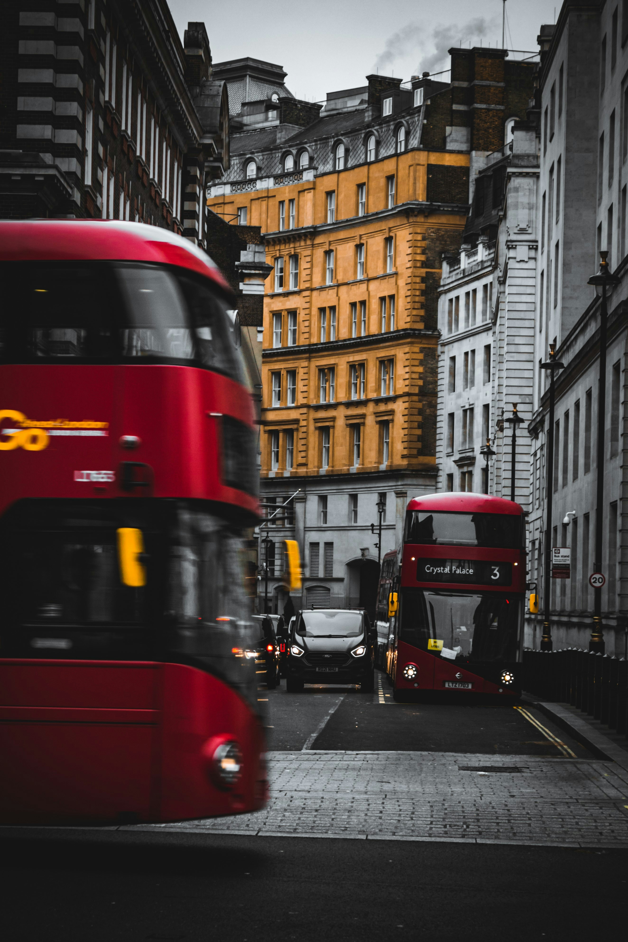A red double decker bus driving down a street photo – Free Street ...